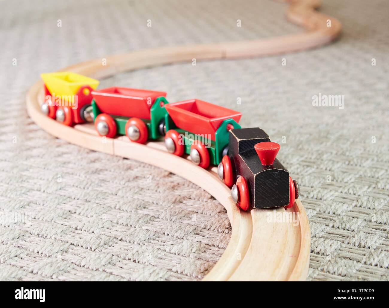 Wooden toy train running on miniature tracks. The black engine pulling ...