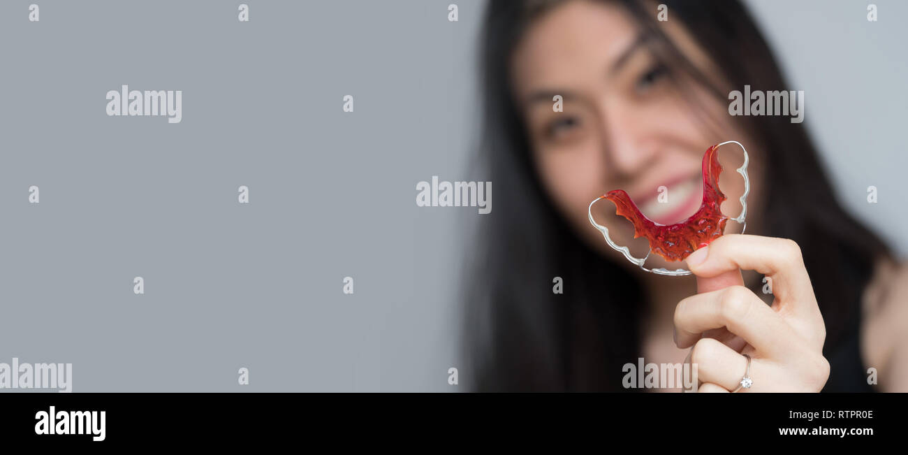 Portrait of beautiful Asian patient woman holding orthodontic retainers ...