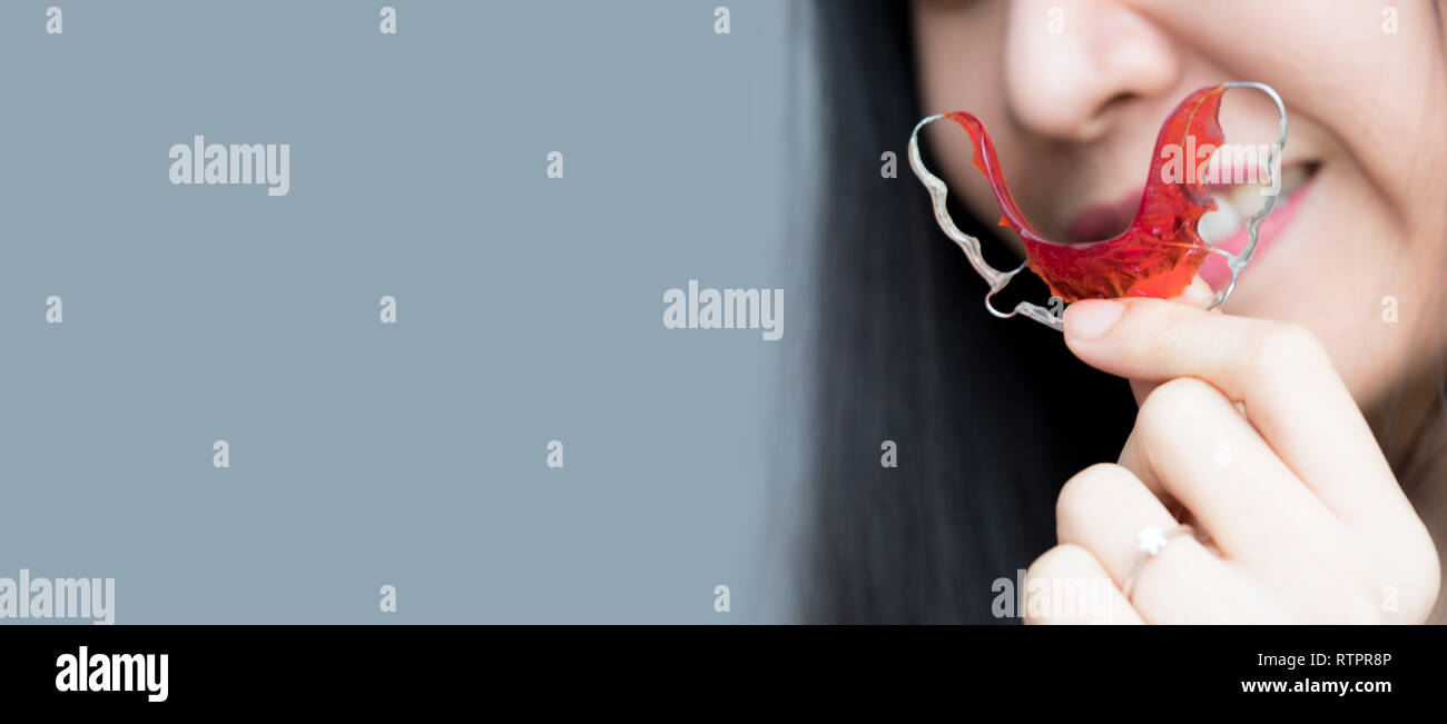 Portrait of beautiful Asian patient woman holding orthodontic retainers ...