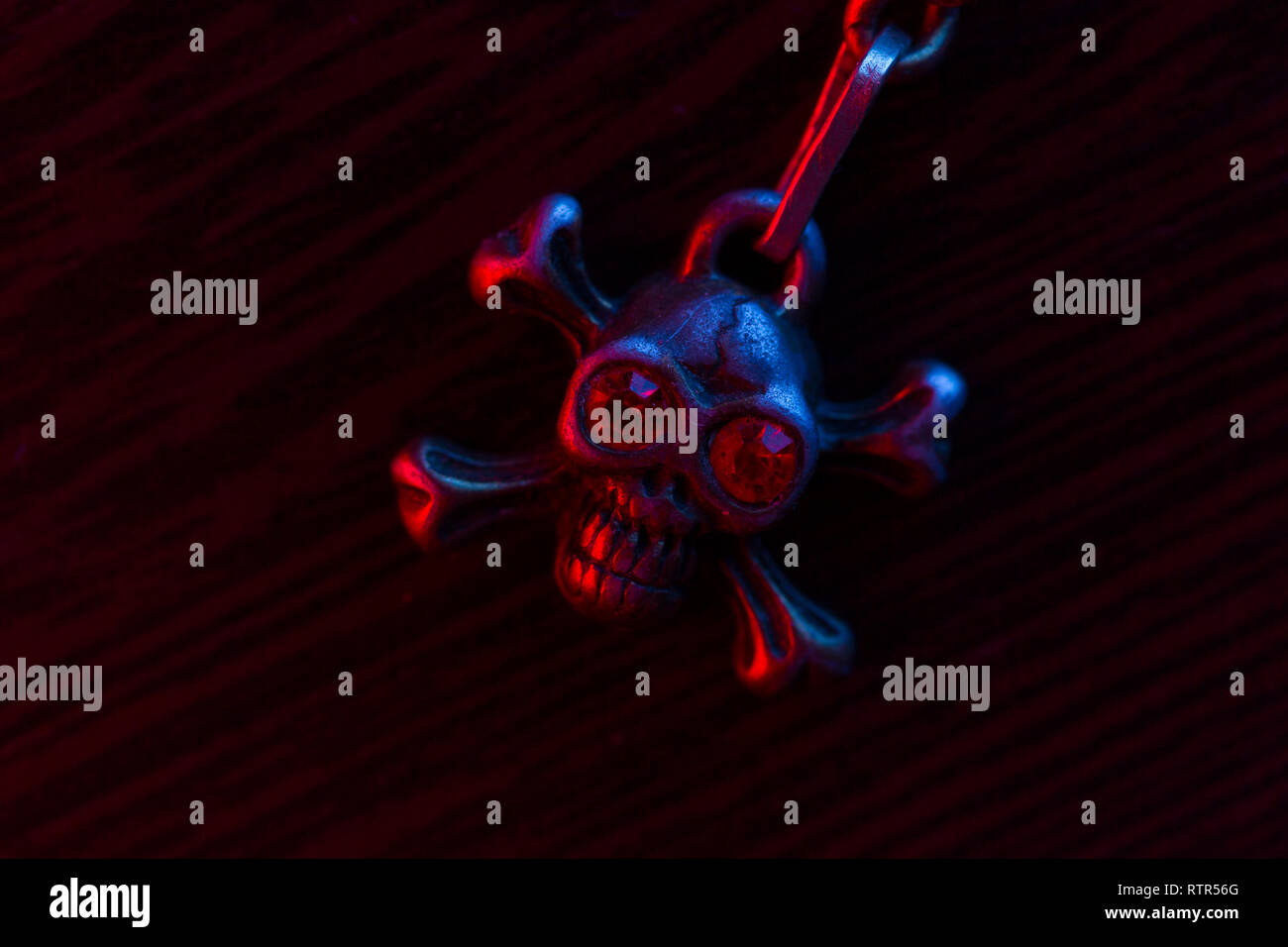 Metal skull chain in neon red and blue light Stock Photo - Alamy