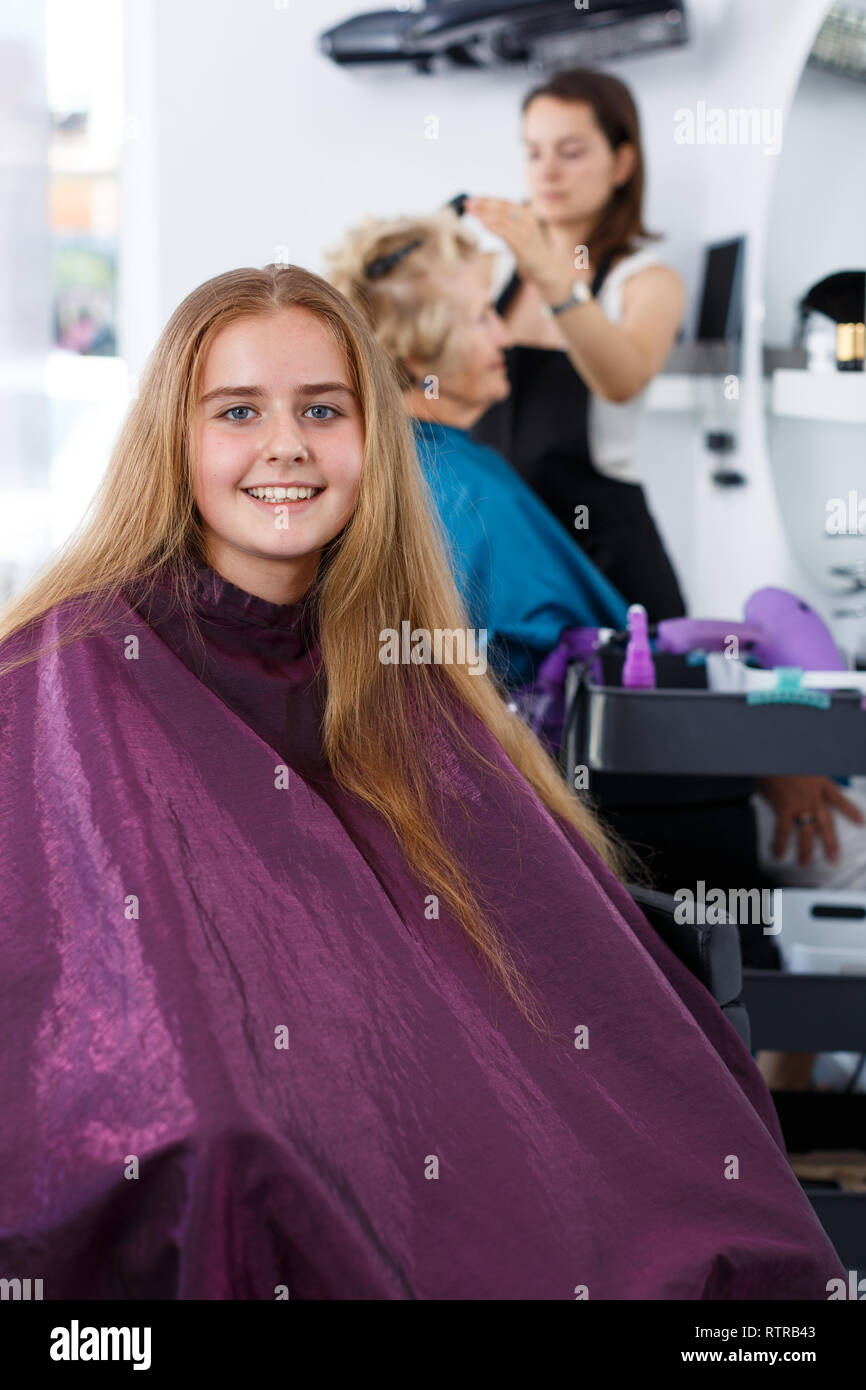 Portrait of smiling long-haired teenage girl waiting for hair styling ...