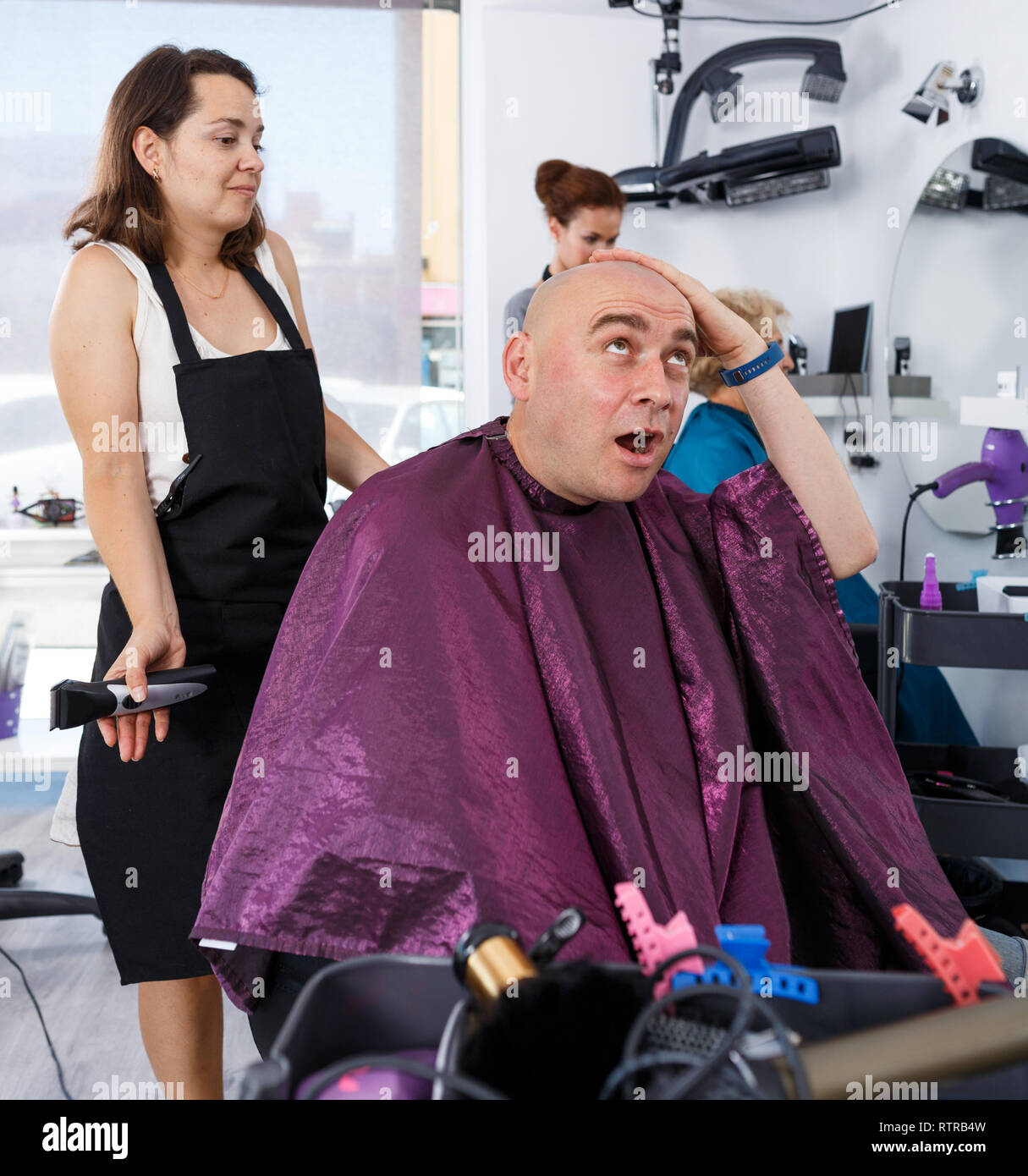 Portrait of dissatisfied male client in hair salon with young ...
