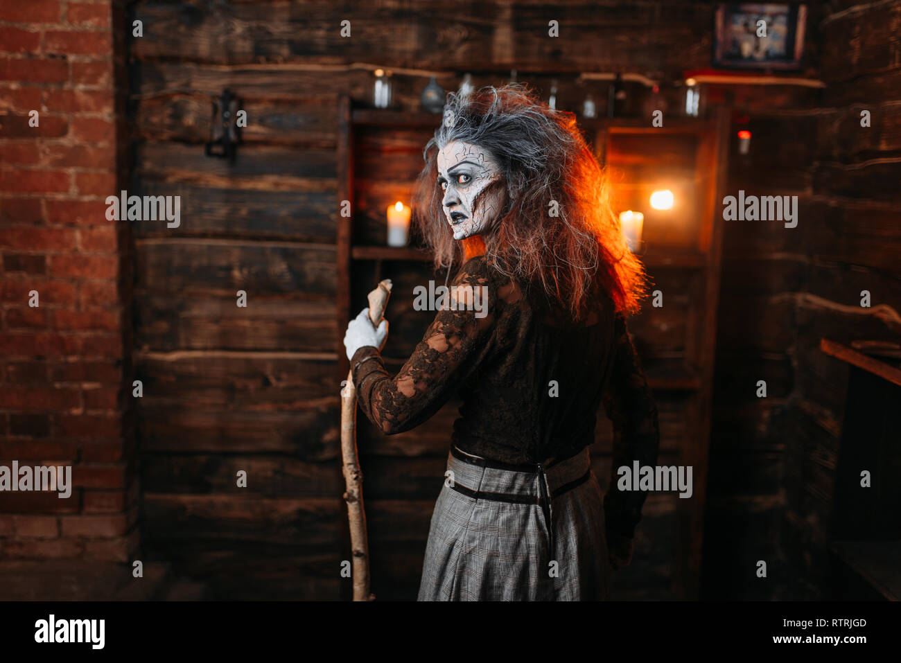 Scary witch with a canein the lair, back view. Spiritual seance of dark ...