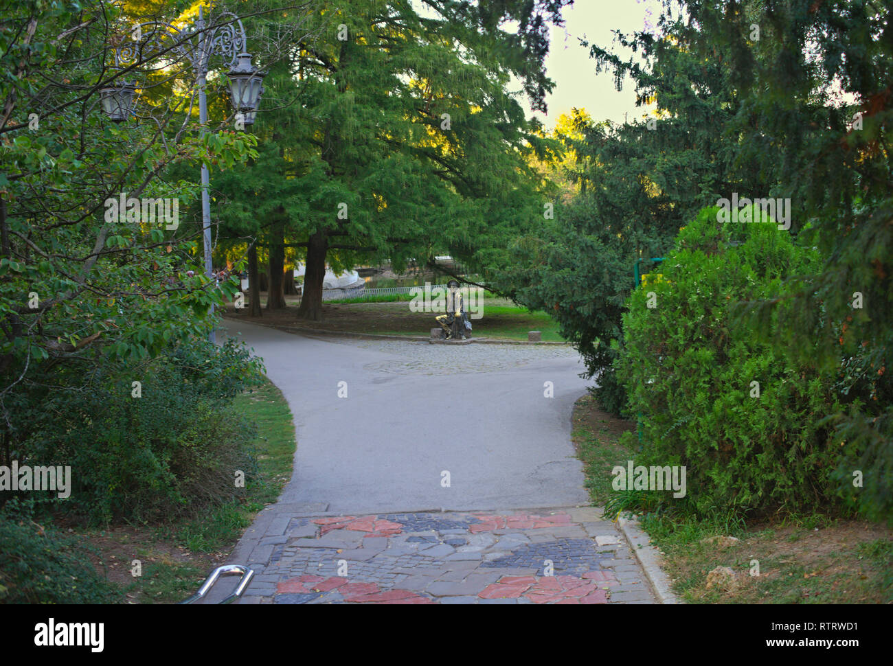 Park path with greenery around and monument at crossroad Stock Photo ...