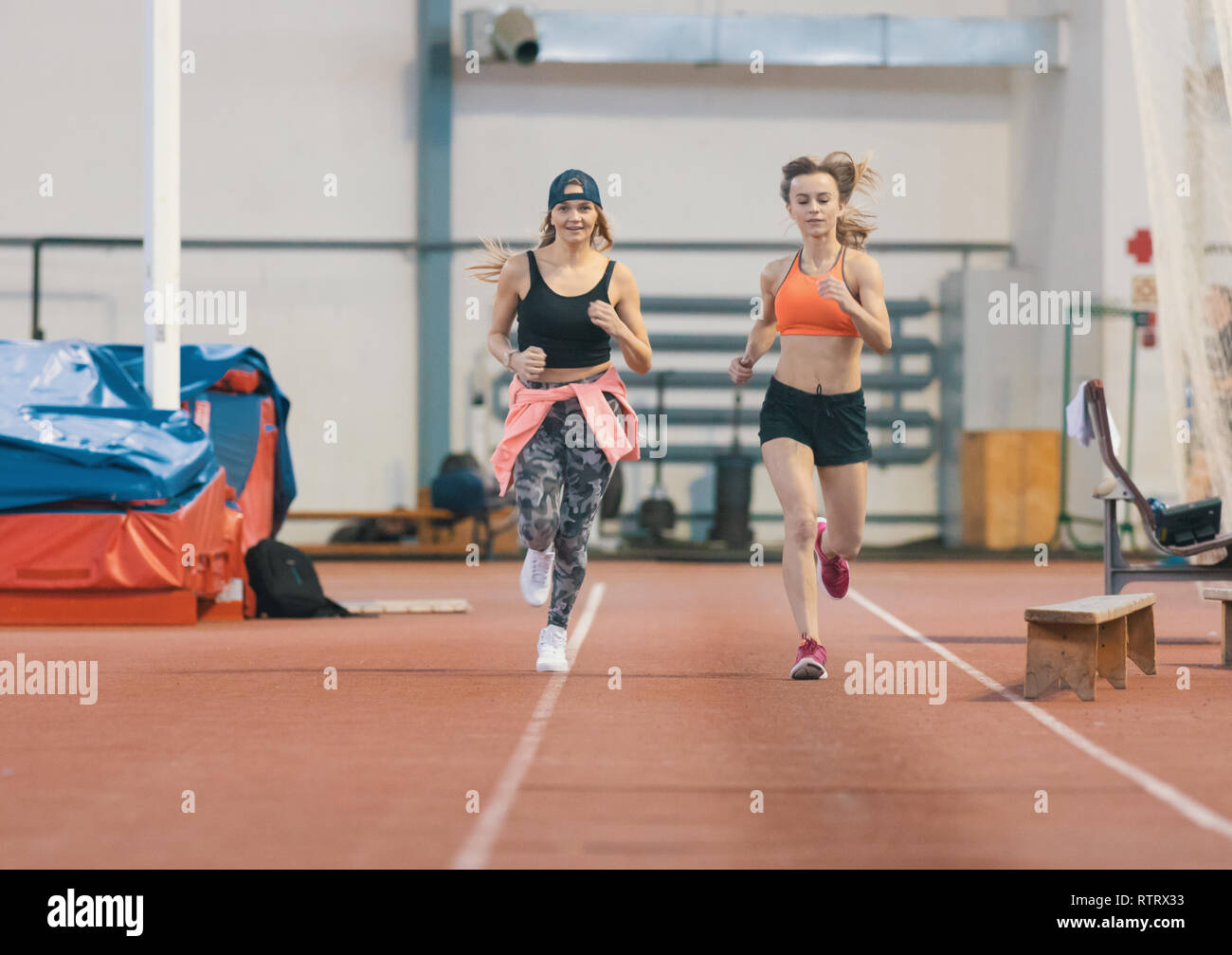 Two young athletic women running in sports arena indoors Stock Photo ...
