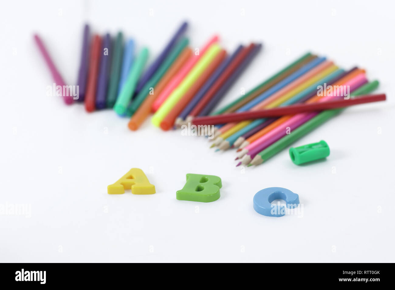 colored pencils and letters of the alphabet on a white background ...