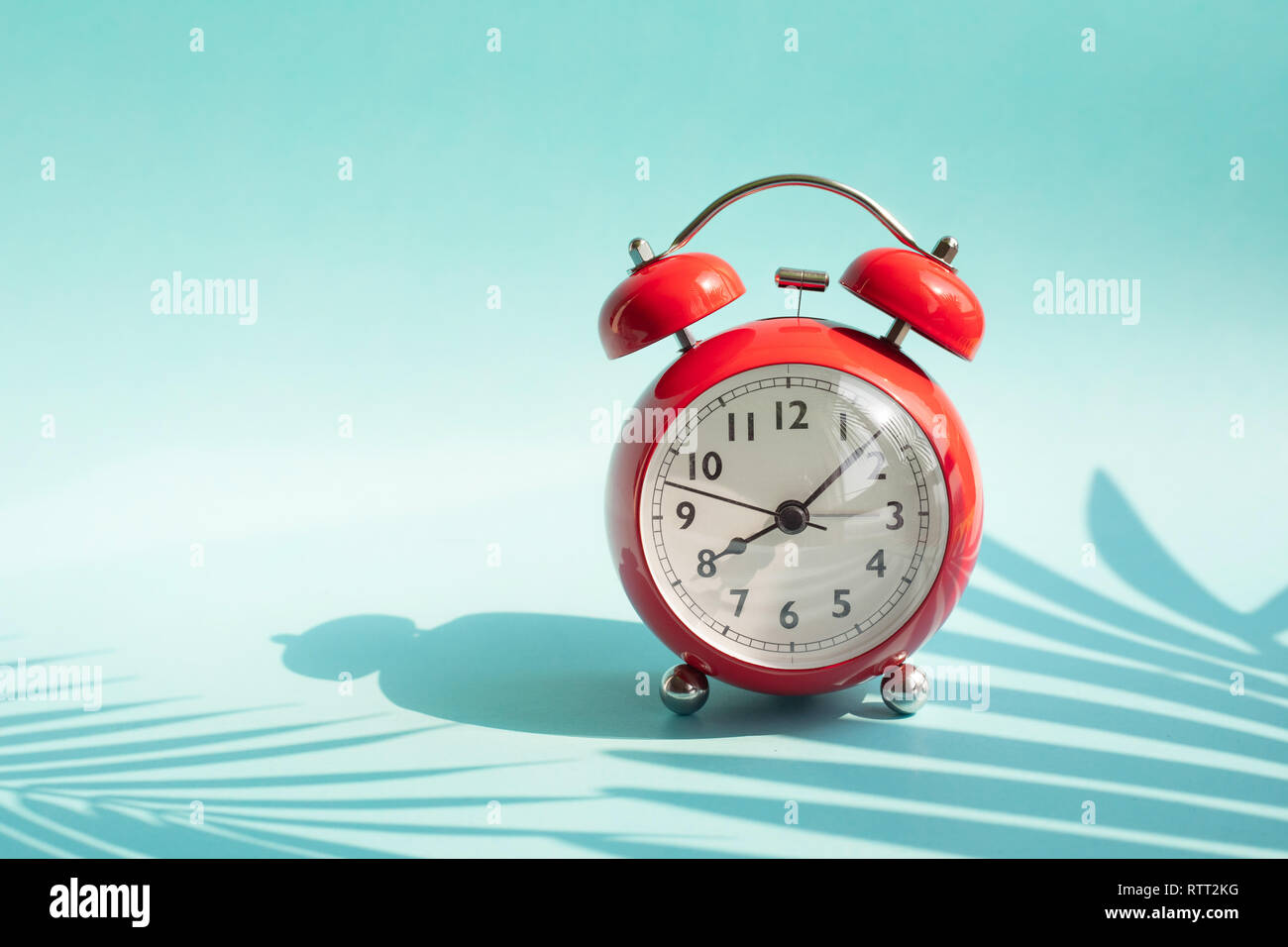 Summer time concepts idea with alarm clock and tropical leaf shadow on ...