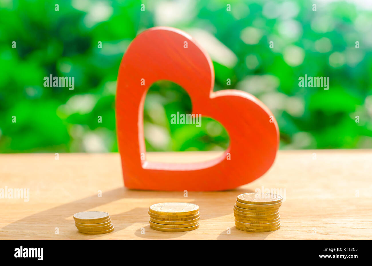 Red wooden heart and money. The concept of saving and accumulation ...
