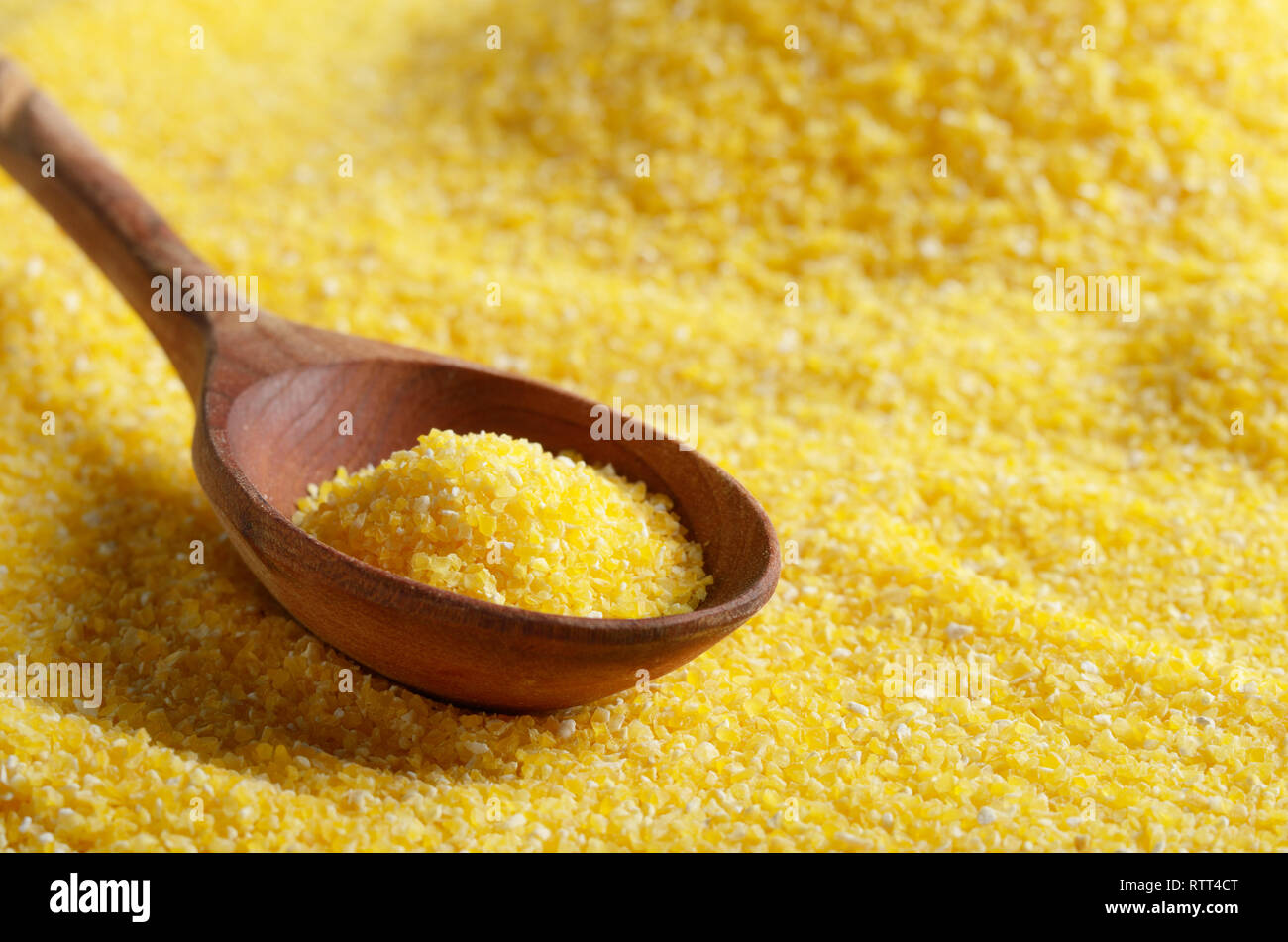 Corn grits yellow background with wooden spoon Stock Photo - Alamy