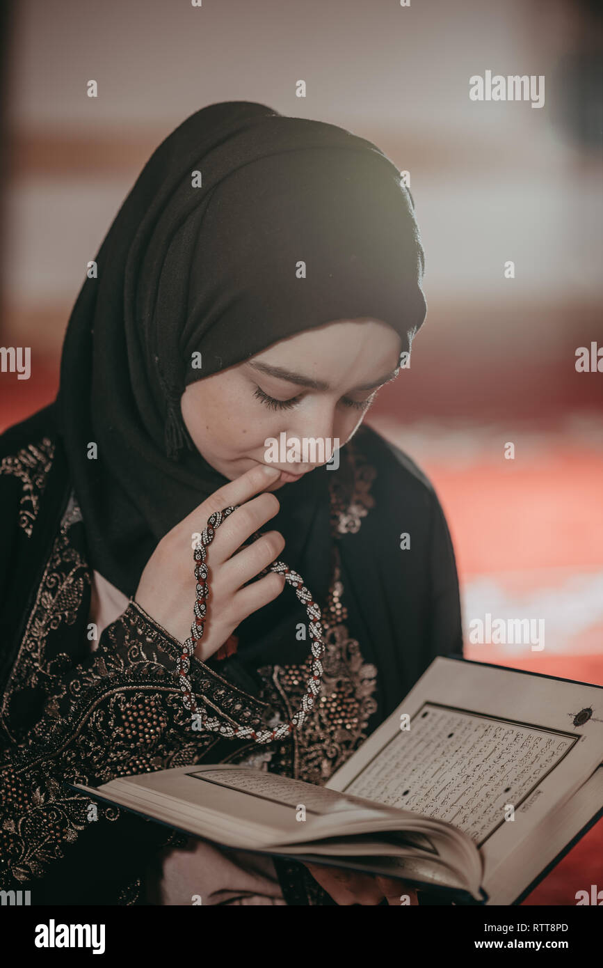 Young beautiful girl reading a holy book of muslim Quran Stock Photo ...