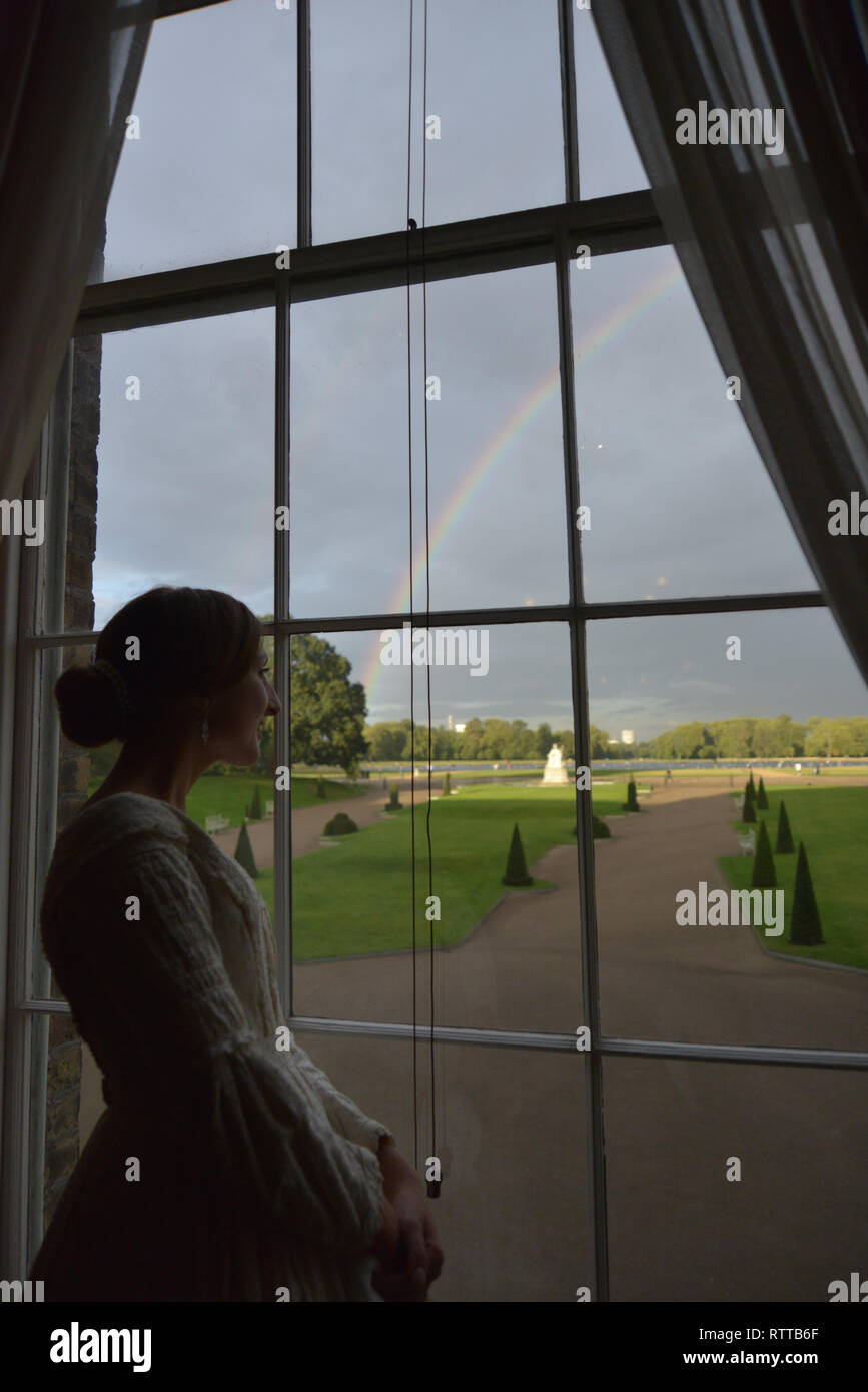 Queen Victoria in silhouette at a window overlooks the ornate gardens ...