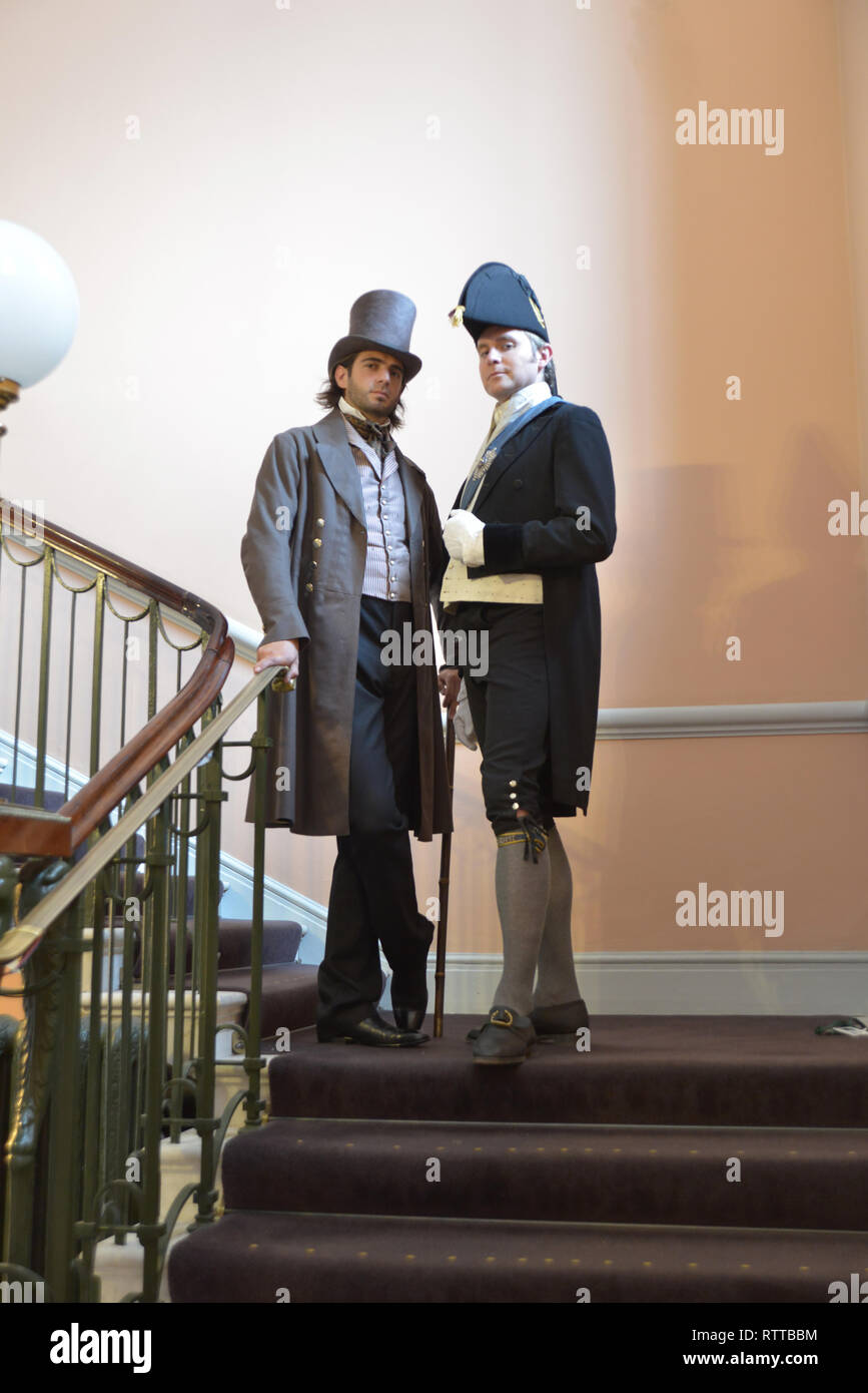 Two Gentlemen in Victorian dress stand together on a stairwell. They ...