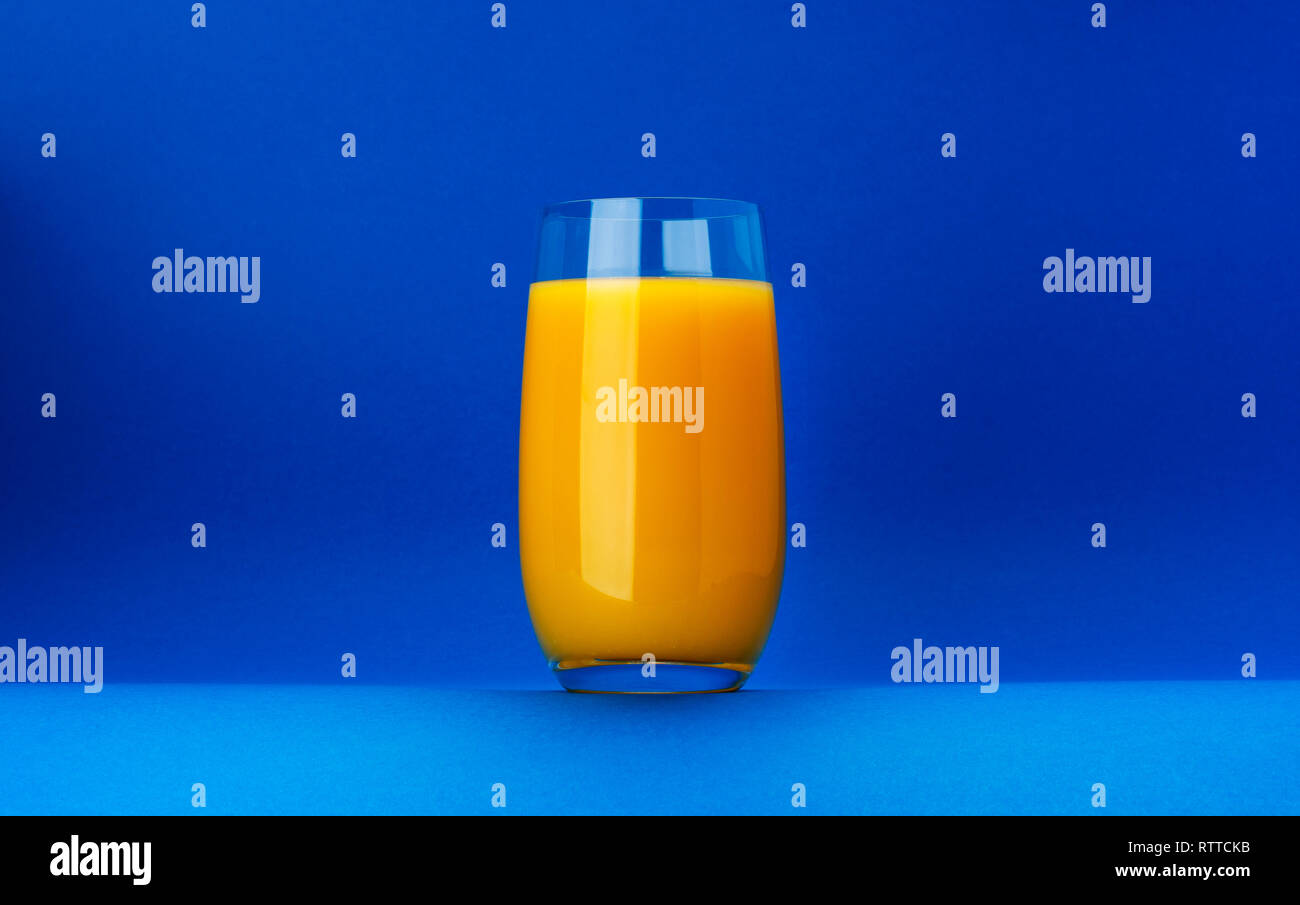 Glass of orange juice isolated on blue background with copy space Stock ...