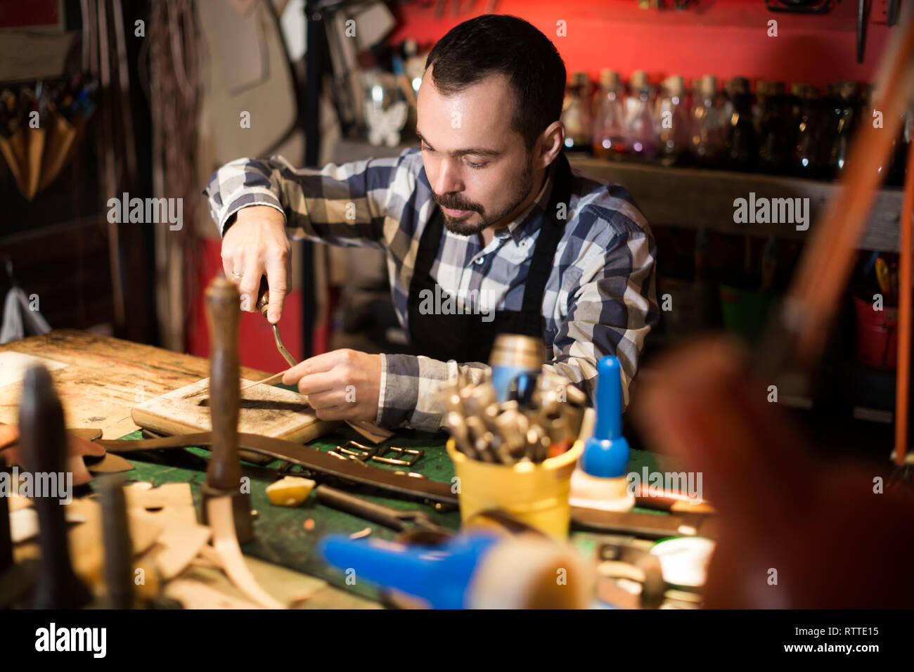 Young man worker processing leather in leather workshop Stock Photo - Alamy