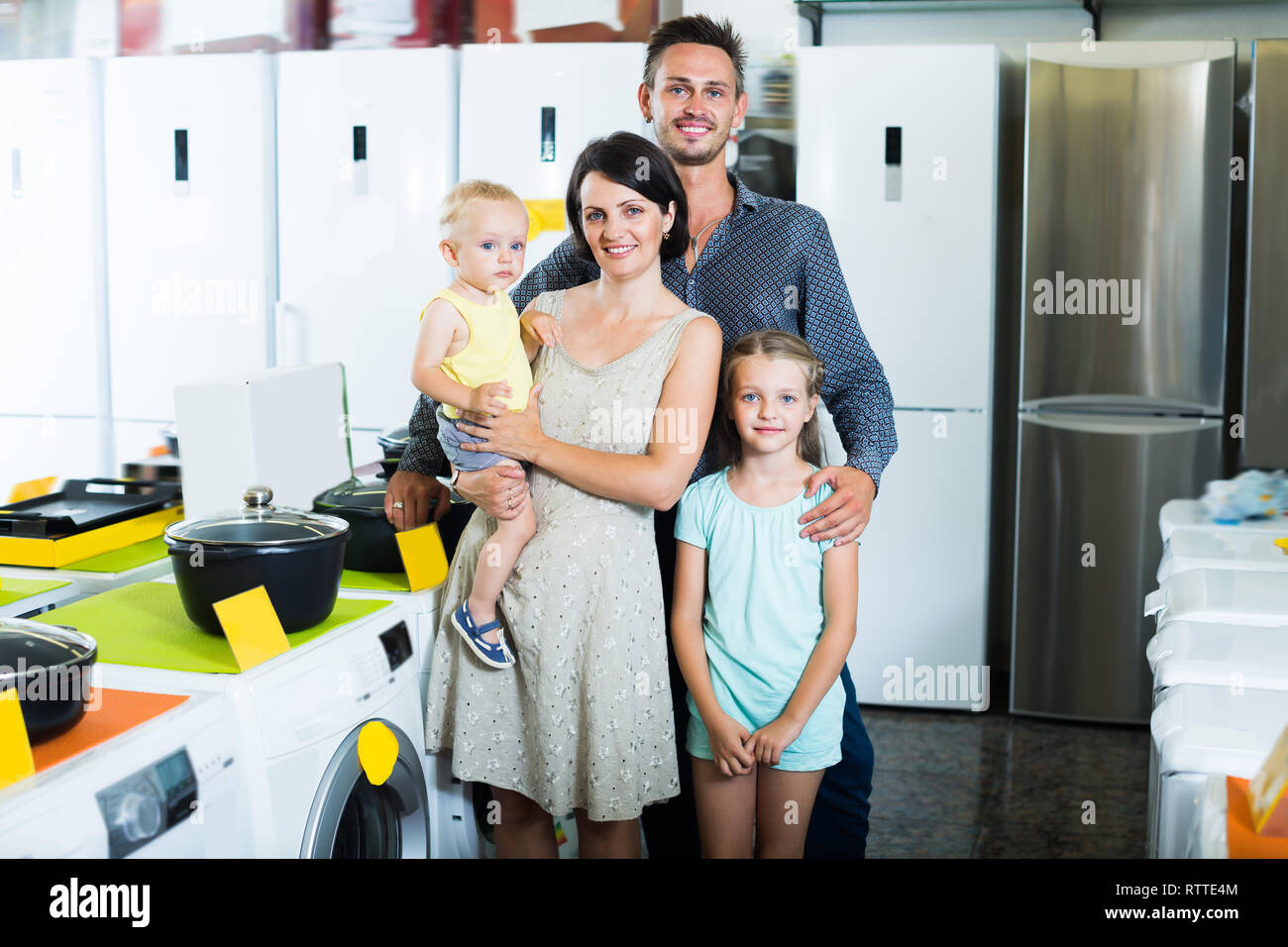 Smiling family with two children shopping together in shop of household ...