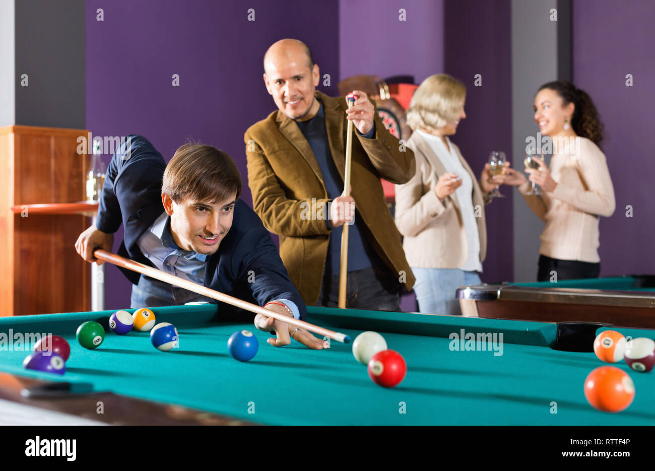 Group of happy friends playing billiards and smiling in night club ...