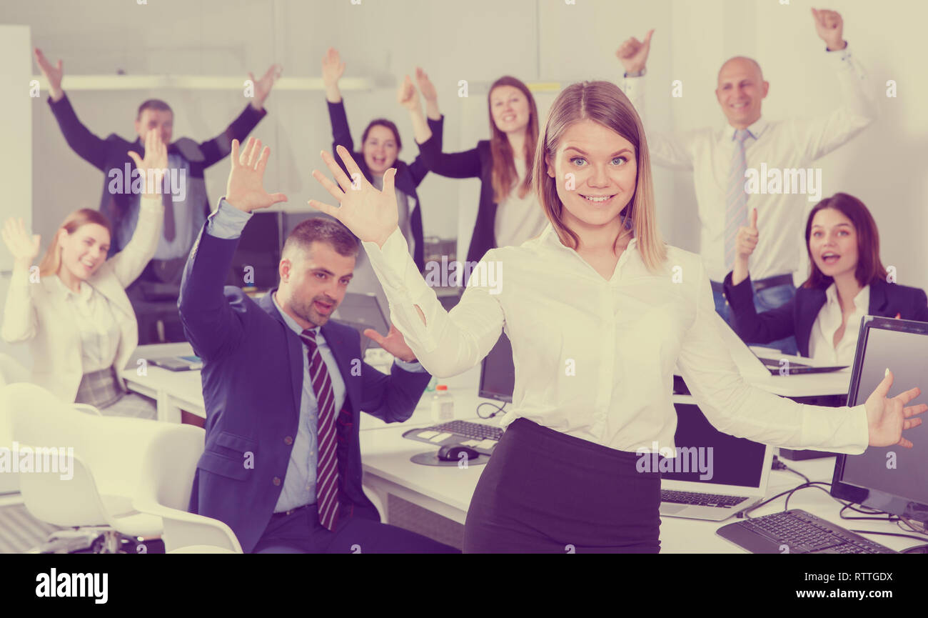 Excited businesswoman with team behind emotionally gesturing and ...