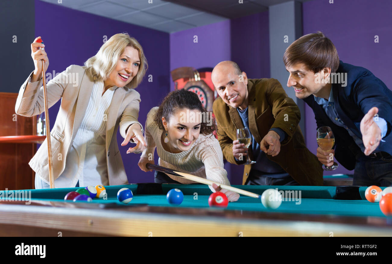 Cheerful positive smiling people playing billiard and darts as hanging ...