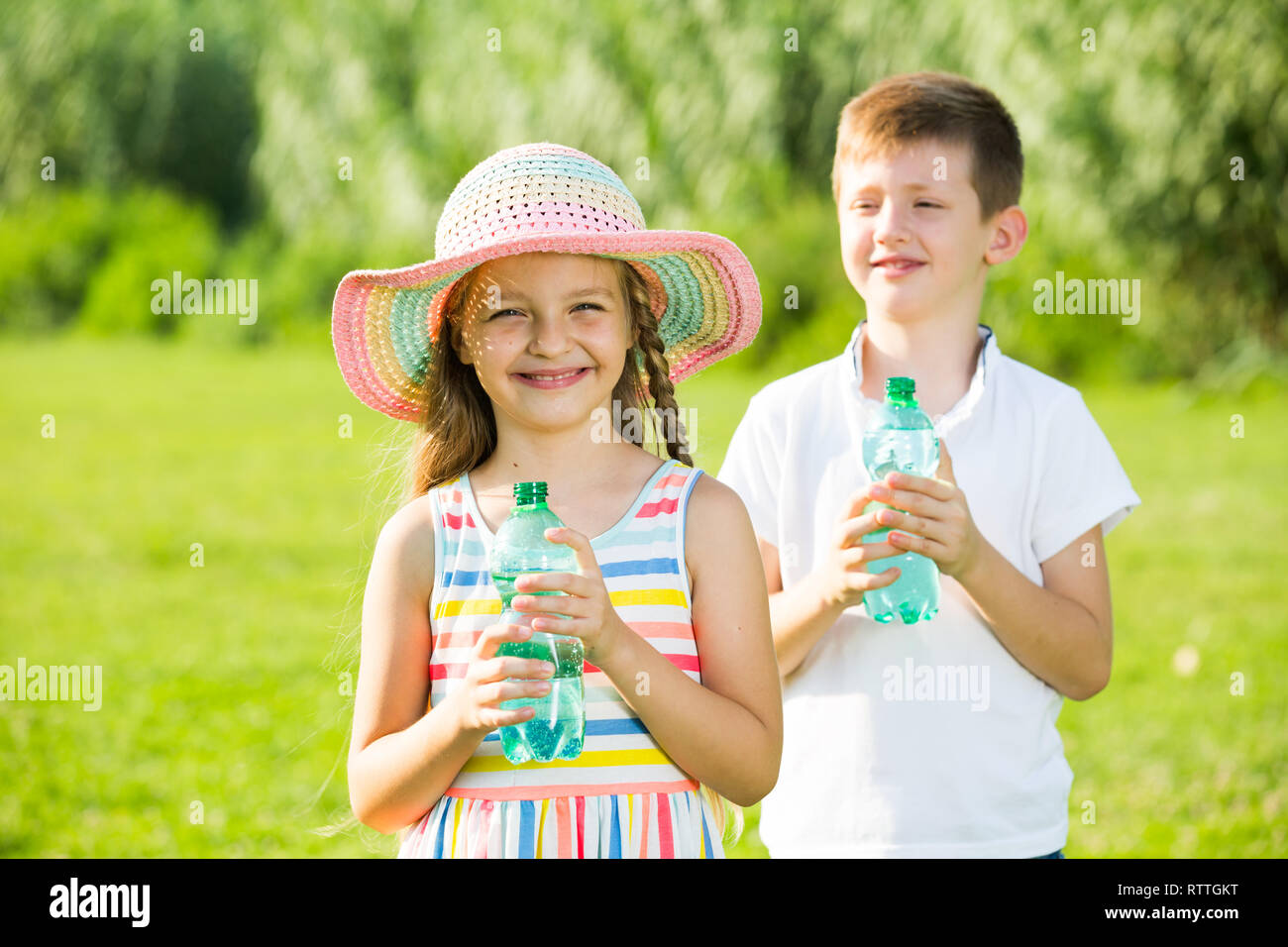 happy two kids in elementary school age drinking water from plastic ...