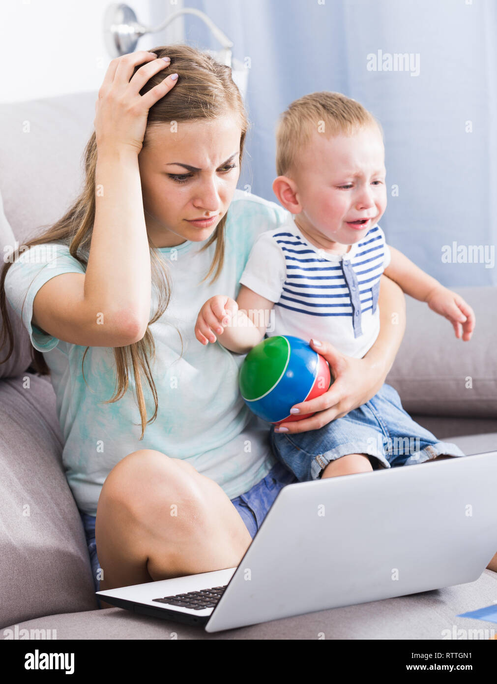 Perplexed woman is having issue with work while child crying at home ...
