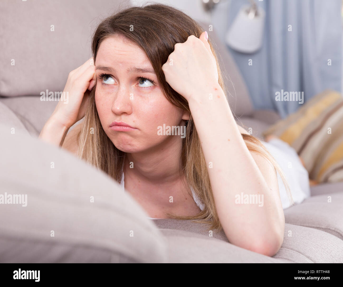 Young female is thoughtful and bored alone at home Stock Photo - Alamy