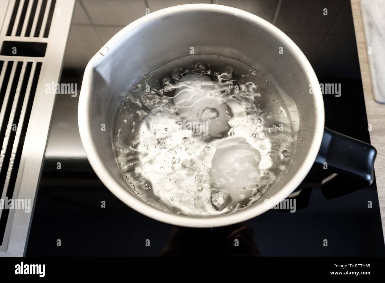 Cooking pot with boling water and white eggs on a stove Stock Photo - Alamy