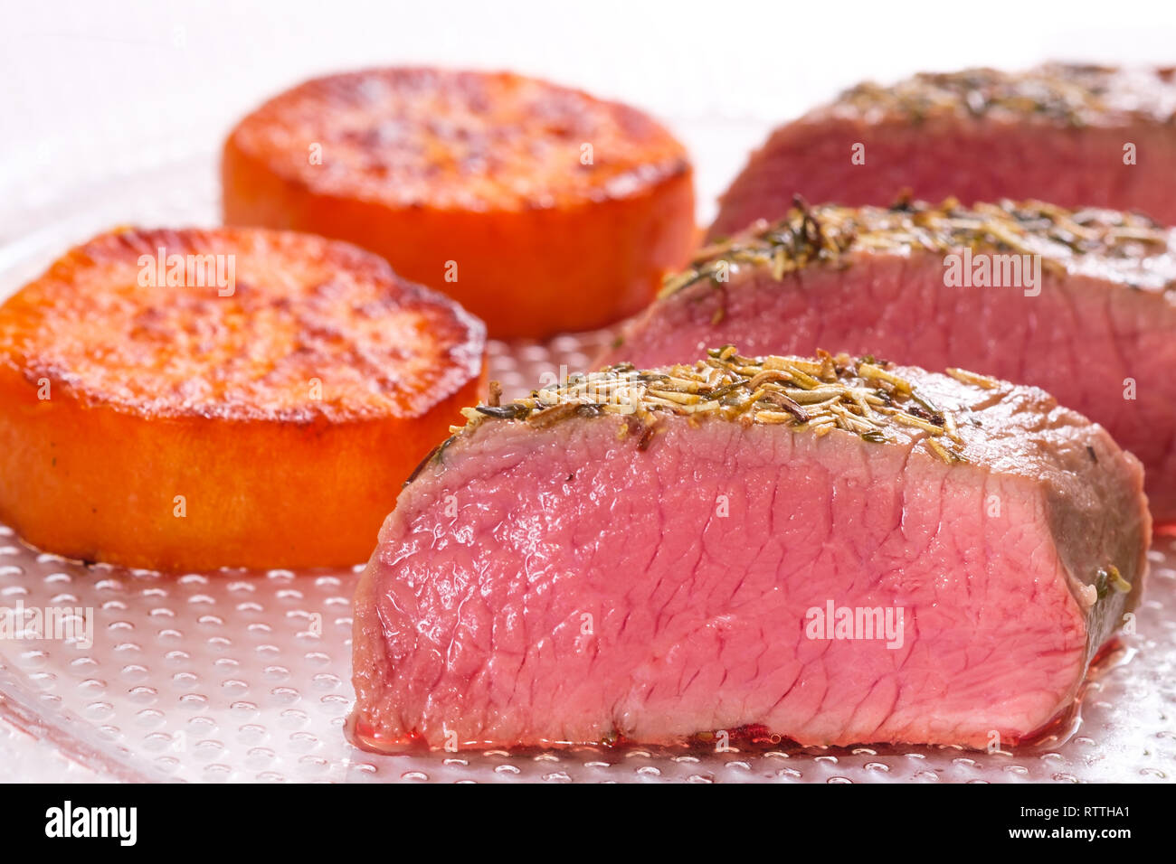 Rare roasted lamb meat with orange yam Stock Photo - Alamy