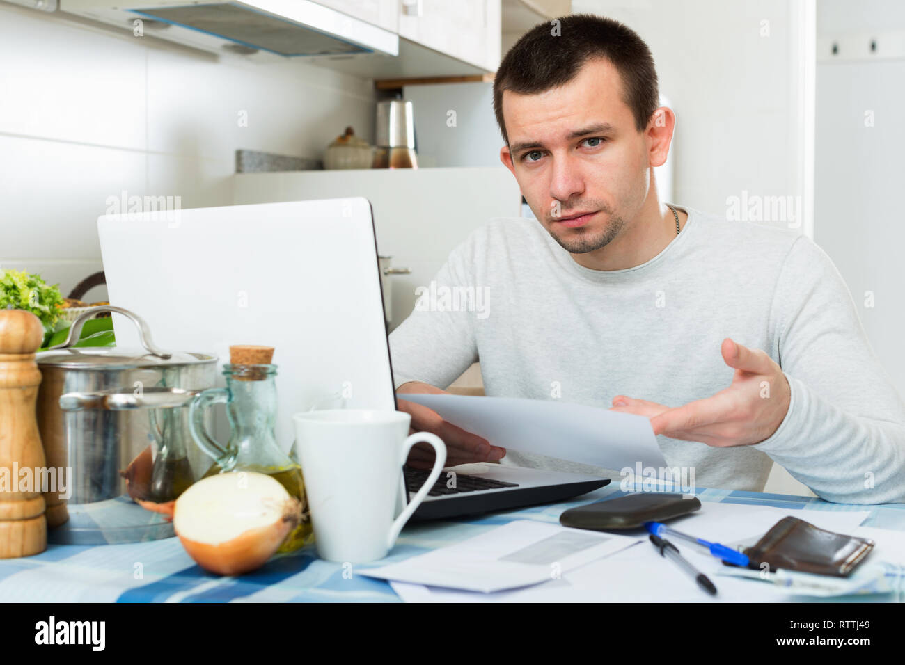 Portrait of efficient guy working with papers and notebook at table in ...
