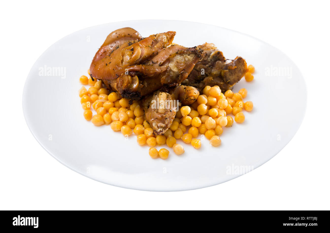 Baked spicy pig trotters served with garbanzos on white plate. Isolated ...