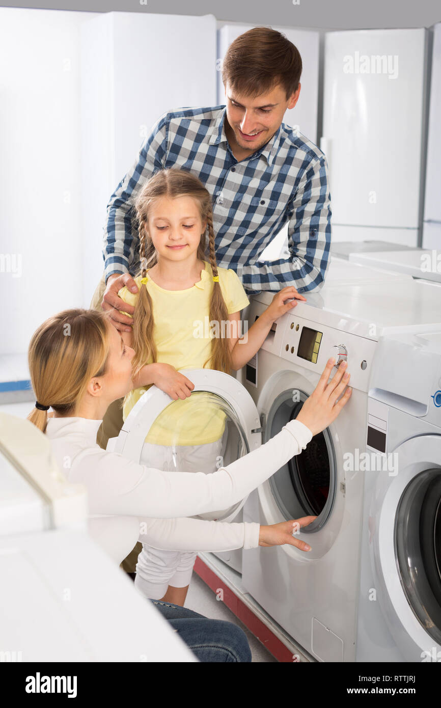 Positive family with girl selecting washing machine in hypermarket ...