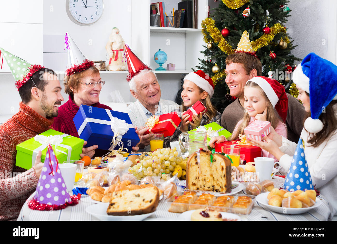 Smiling family members handing presents to each other during Christmas ...