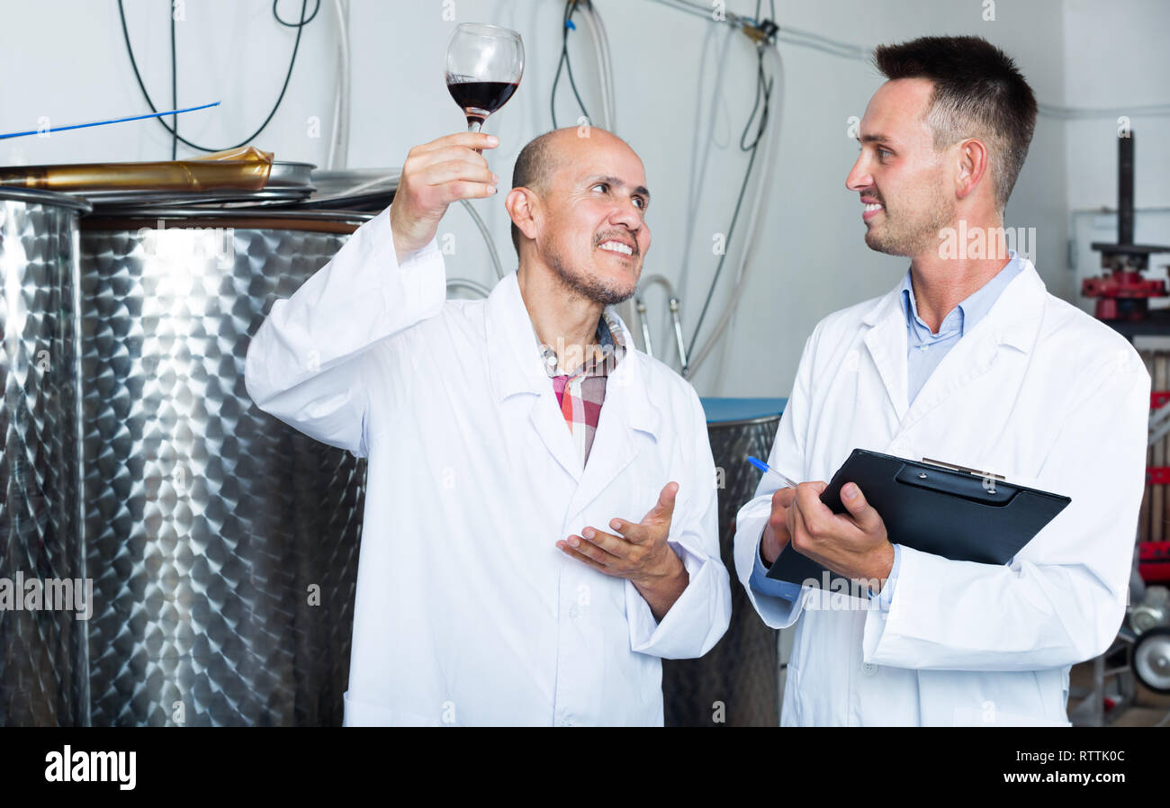 Happy two factory workers in uniform standing together and examining a ...