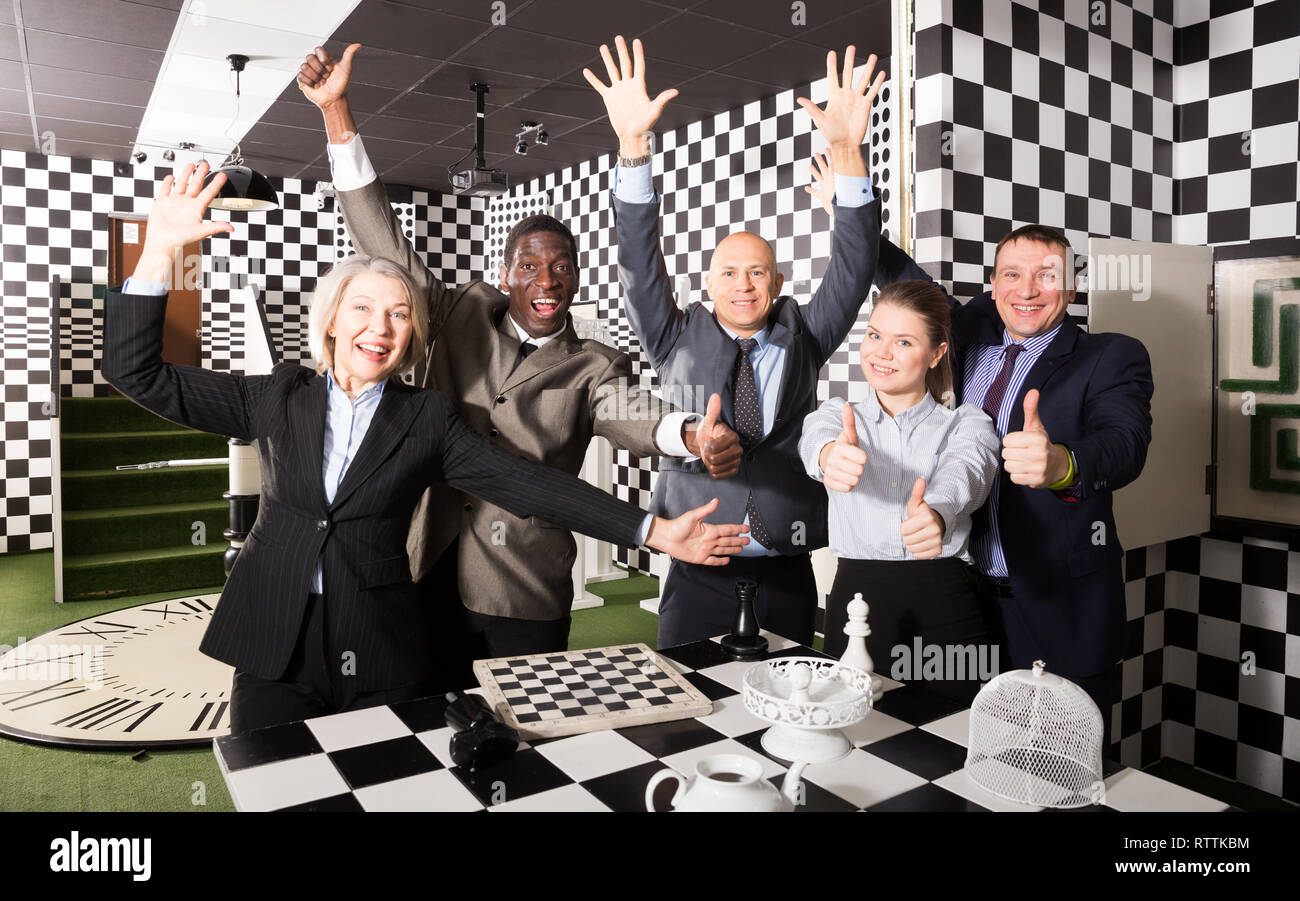 Happy laughing businesspeople playfully posing together in escape room ...