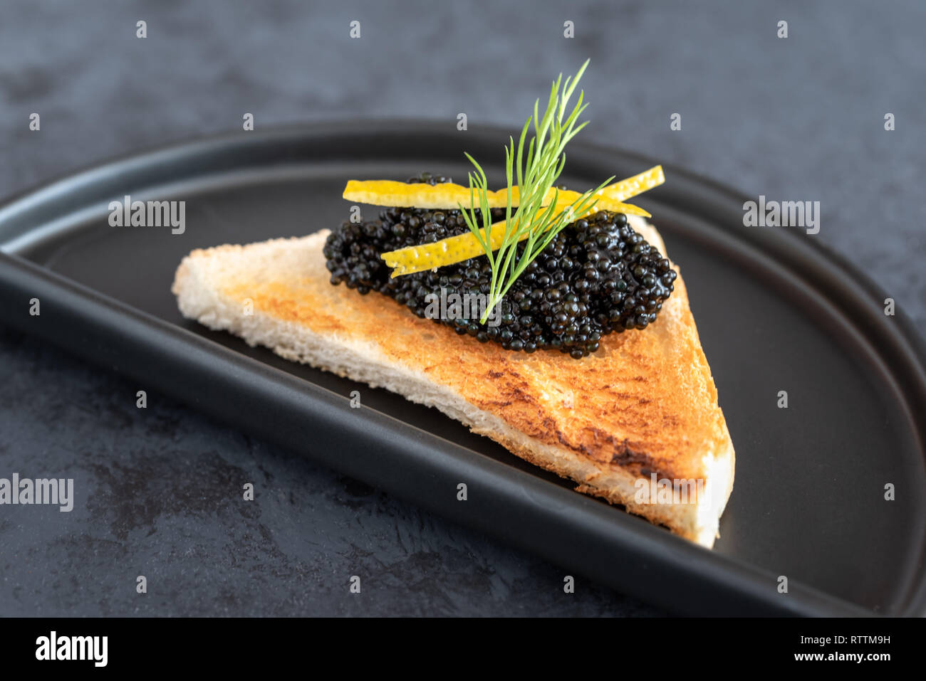 Appetizer toast bread with black caviar decorated by lemon pill and ...