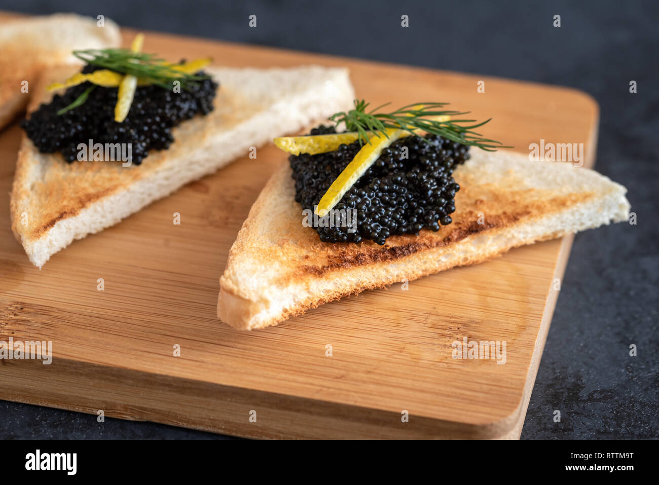 Appetizer toast bread with black caviar decorated by lemon pill and ...