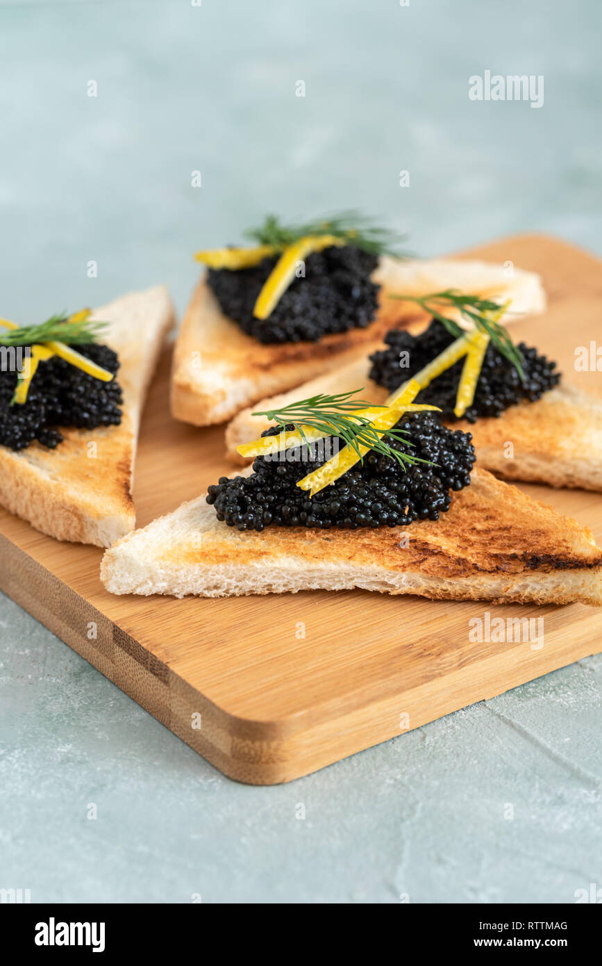 Appetizer toast bread with black caviar decorated by lemon pill and ...
