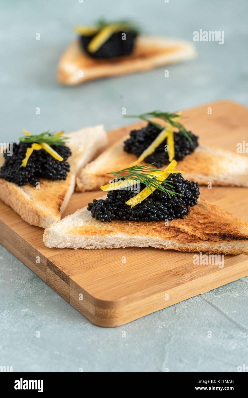 Appetizer toast bread with black caviar decorated by lemon pill and ...