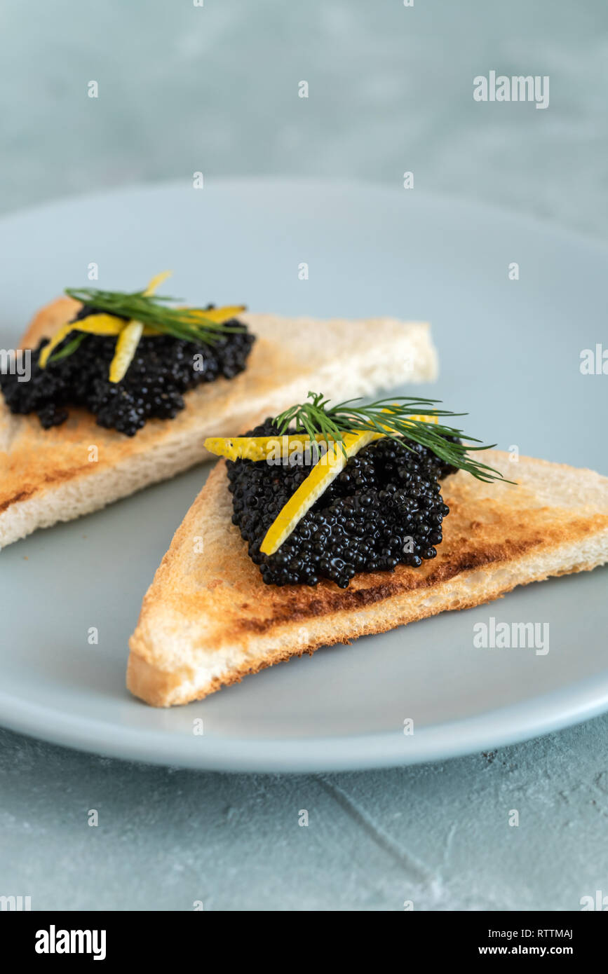 Appetizer toast bread with black caviar decorated by lemon pill and ...