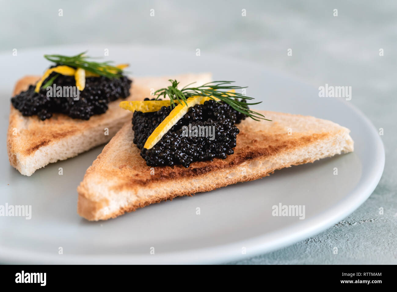 Appetizer toast bread with black caviar decorated by lemon pill and ...