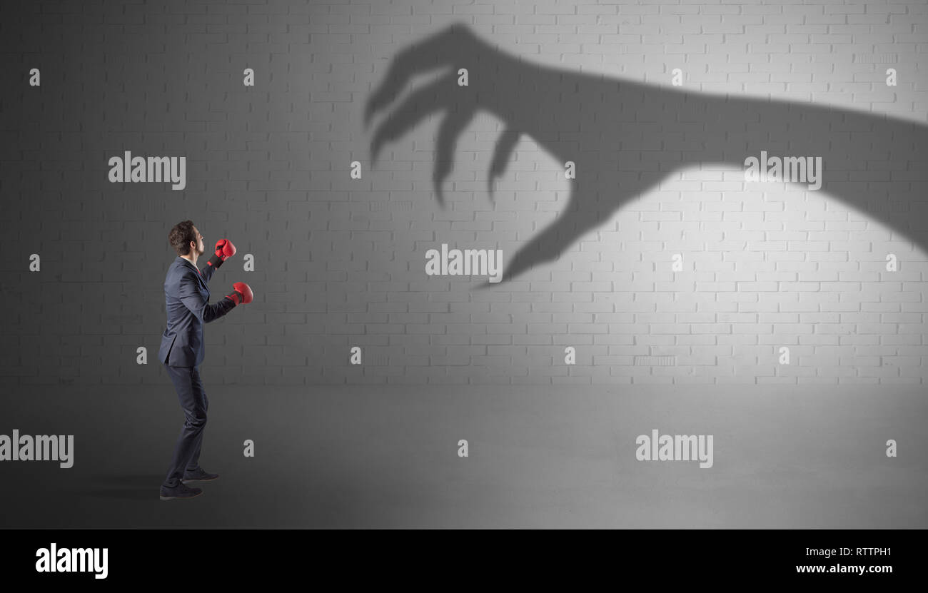 Tiny businessman fighting with scary hand shadow Stock Photo - Alamy