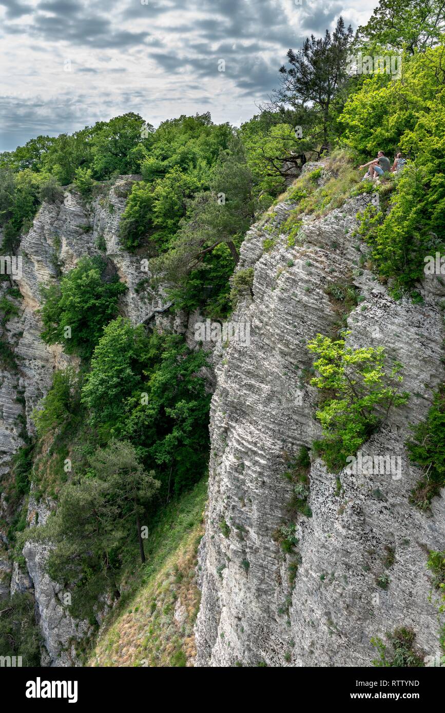 Mountain with a steep green rocky slope. Several people are extremely ...