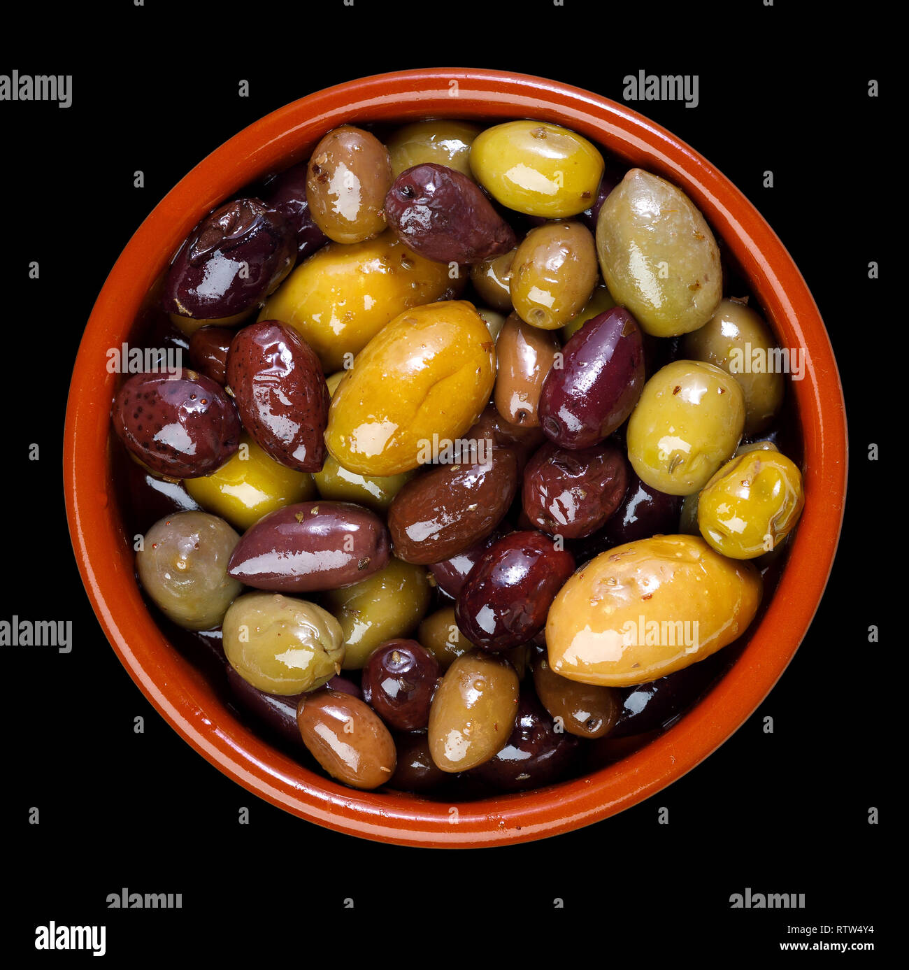 green and purple, mixed olives in clay bowl - isolated on black ...