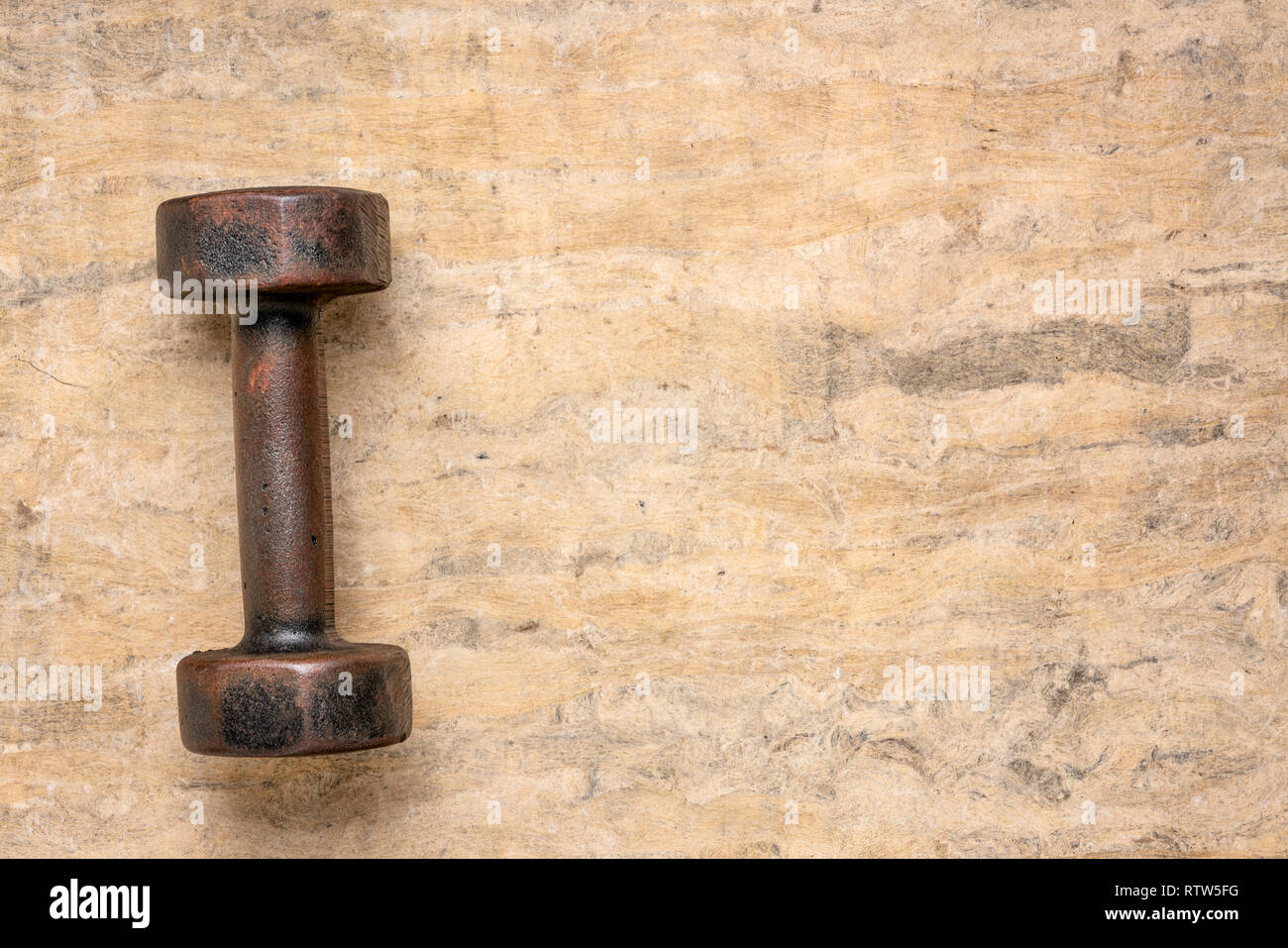 old rusty dumbbell on textured handmade bark paper with a copy space ...