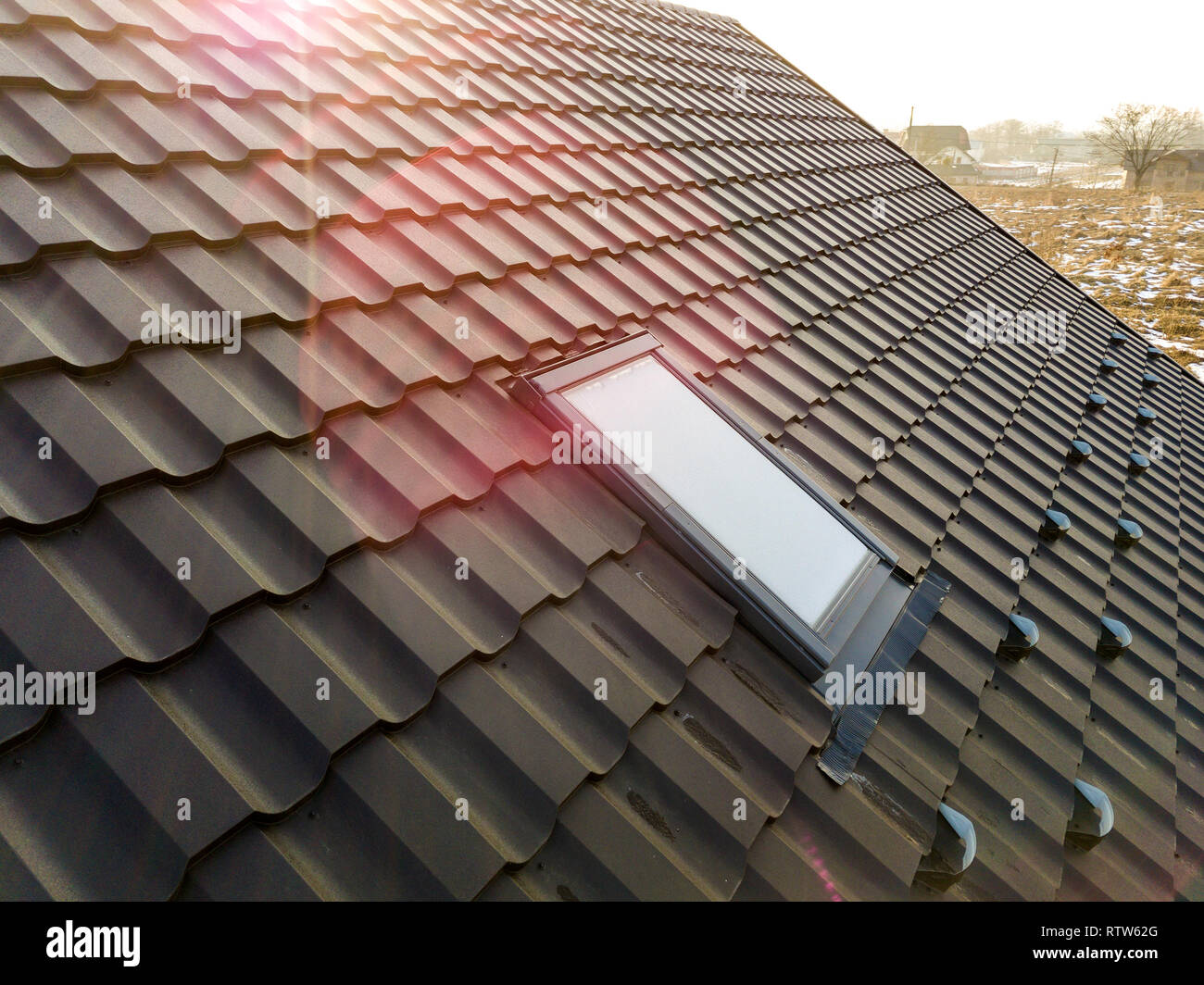 Close-up of new attic plastic window installed in shingled house roof ...