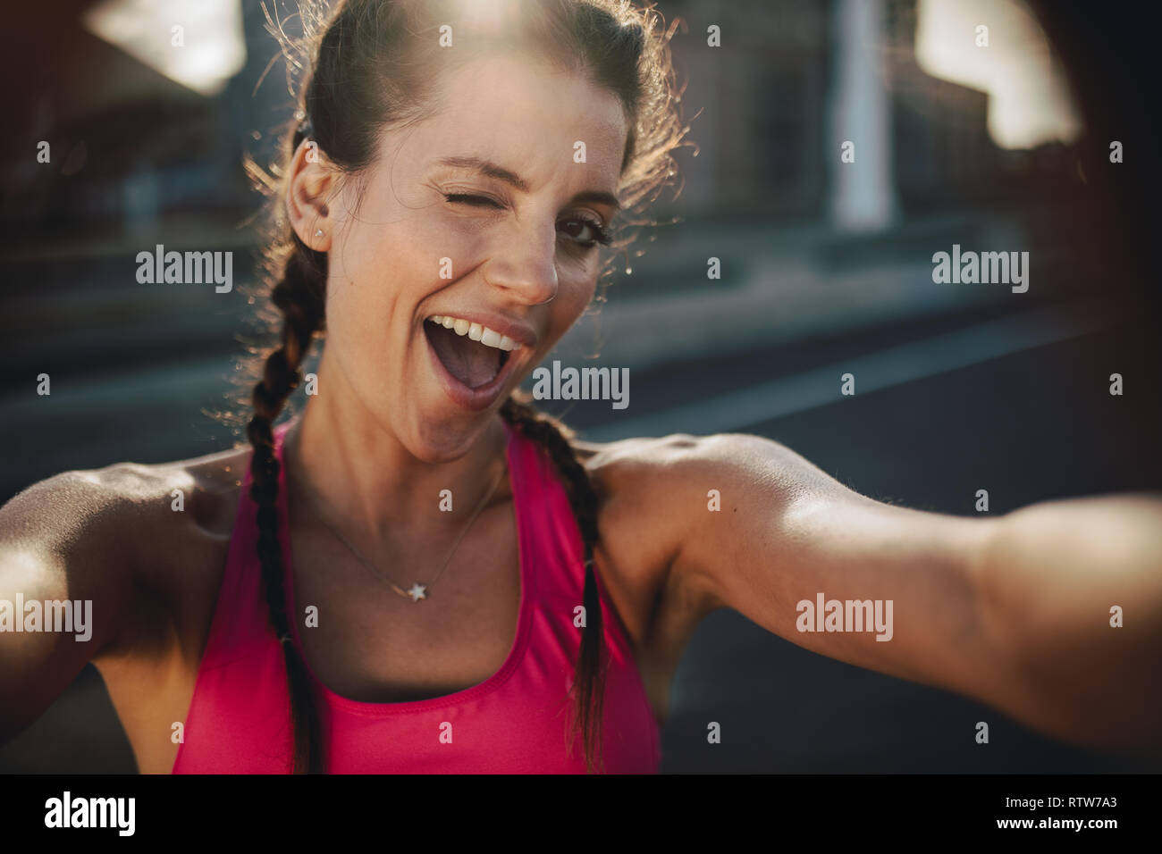 Female runner standing outdoors in morning and winking at camera ...