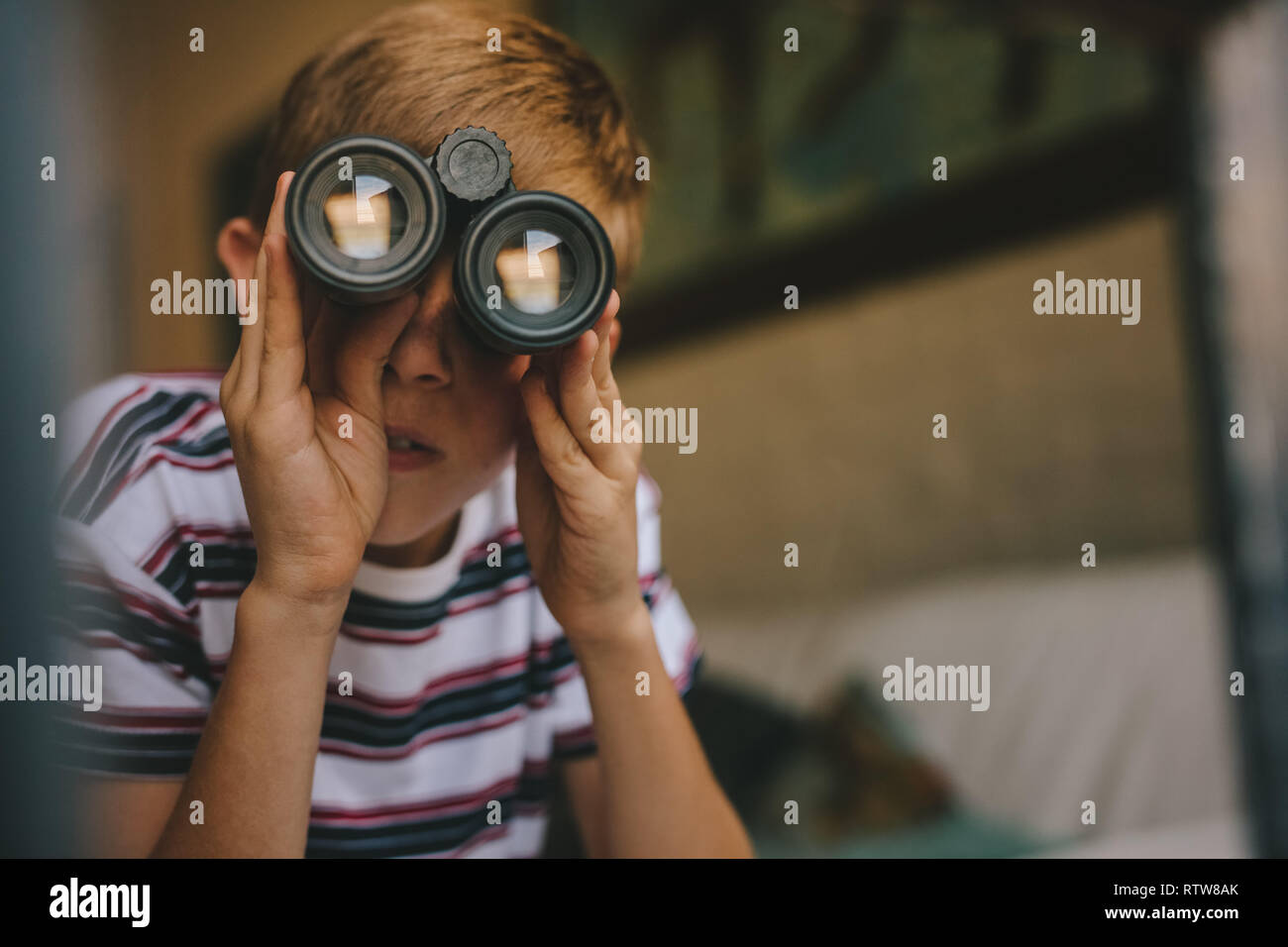 Small boy looking outside window using binoculars. Boy looking through ...