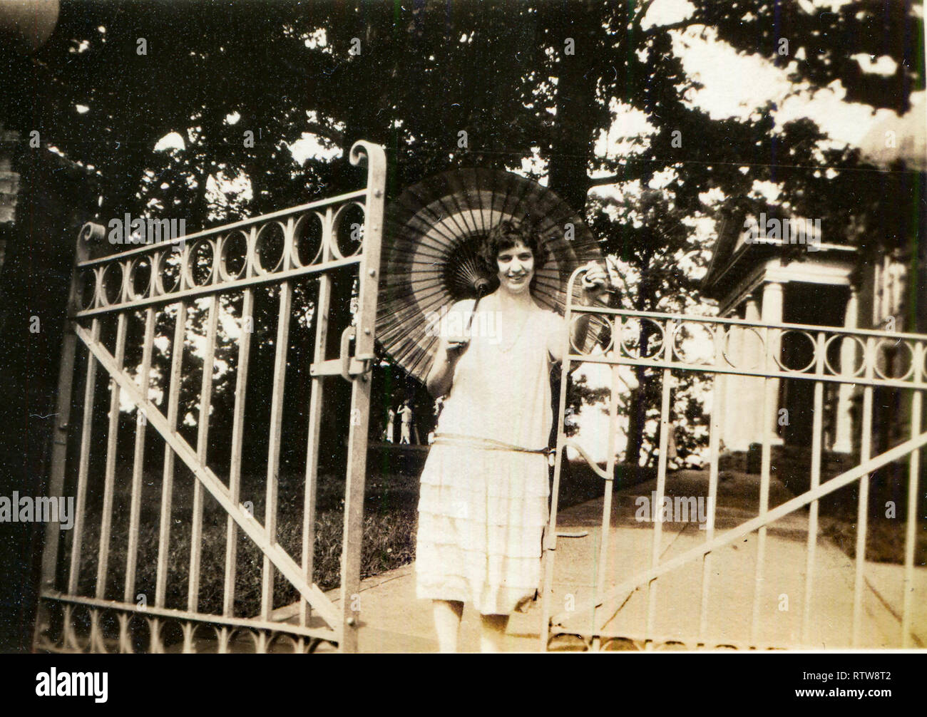 America, USA, 1920, A young girl stands at a beautiful gate with a ...