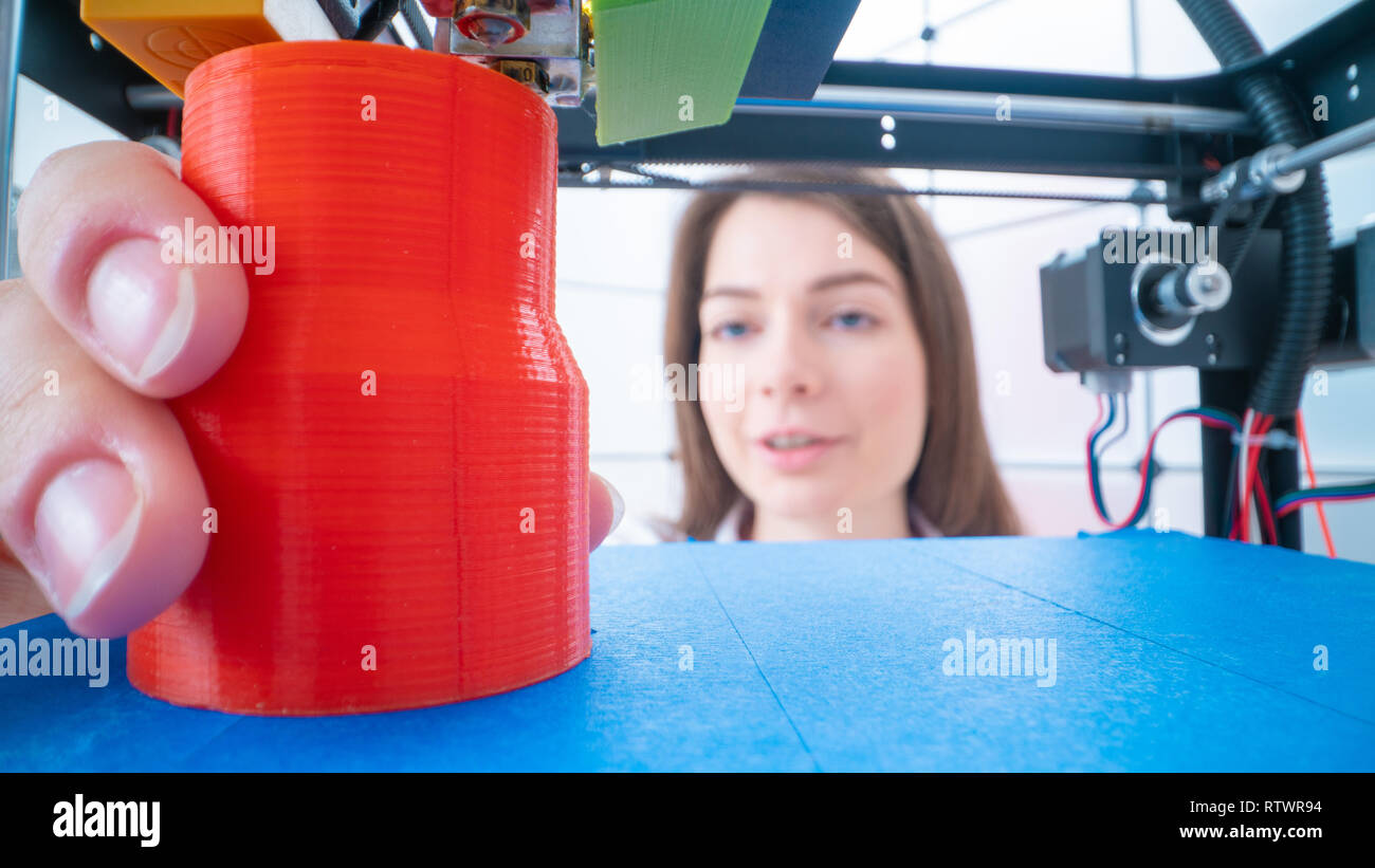 Young women designer in 3d printing lab. Girl takes the finished detail ...