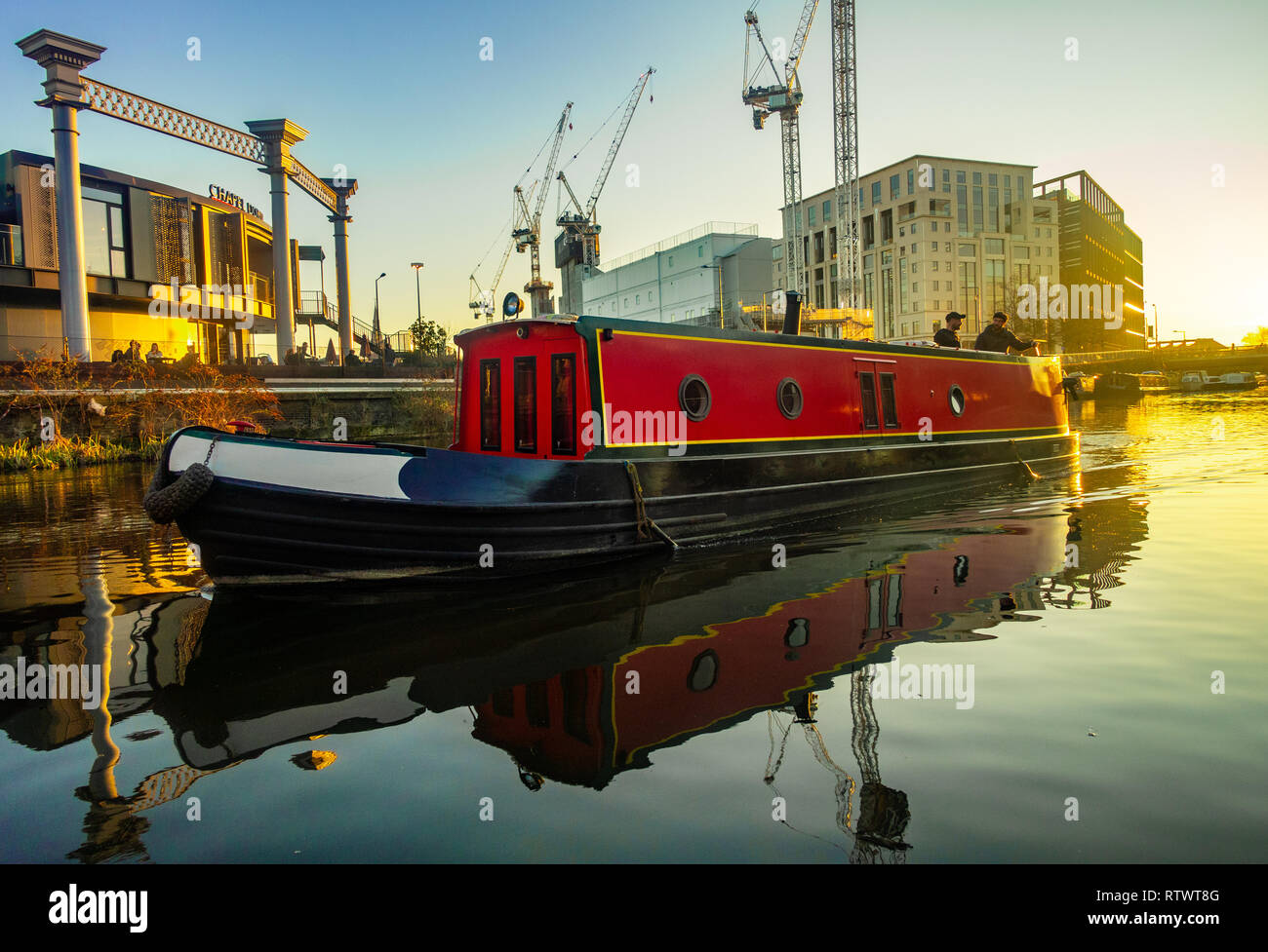a sunset view across the Regents Canal of Narrowboat passing the ...