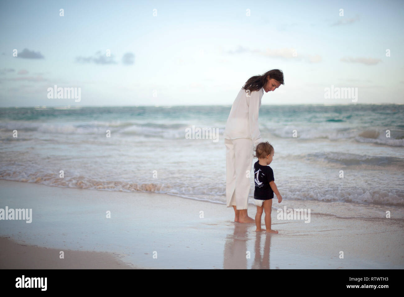 On sunset sand beach mother and little baby explores the ocean Stock ...